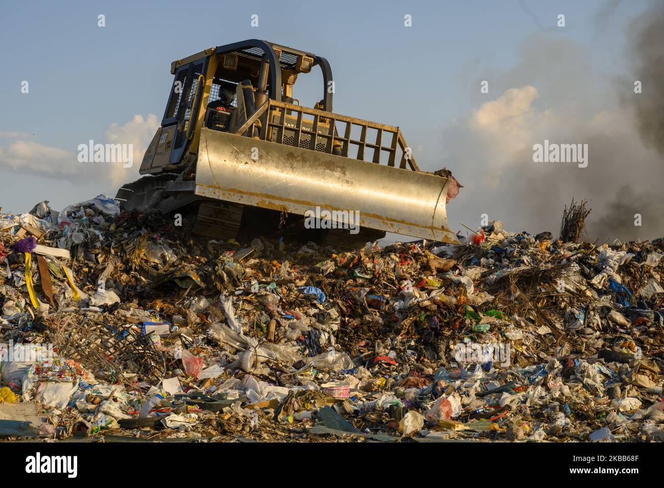 Officers use heavy equipment to separate burning rubbish at the ...