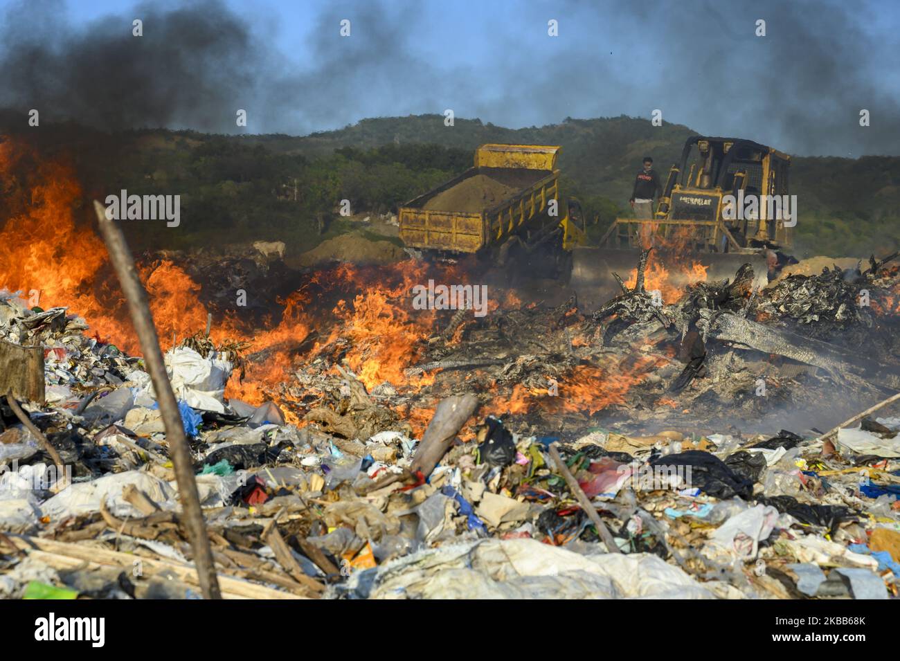 Officers use heavy equipment to separate burning rubbish at the ...