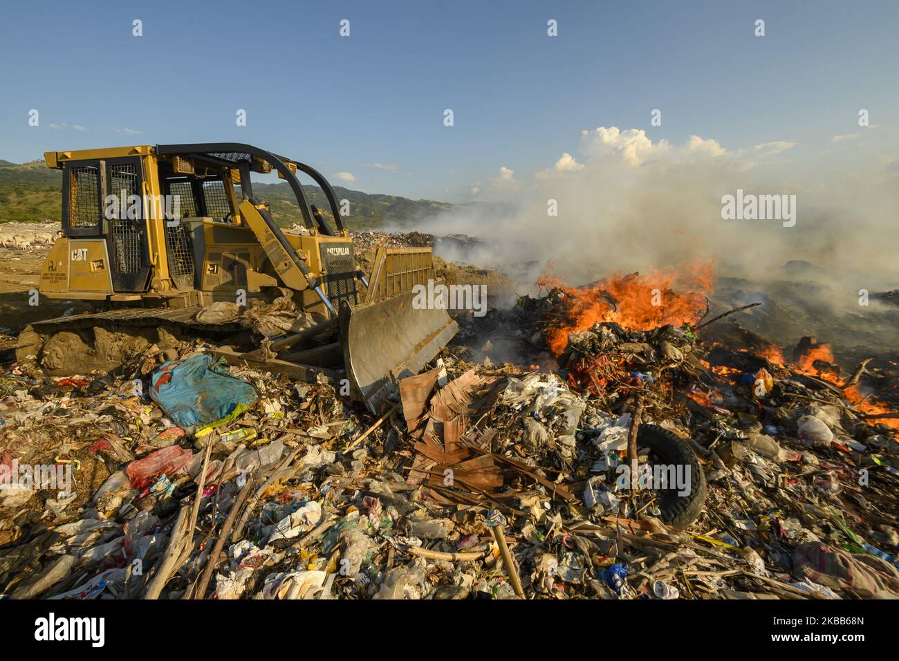 Officers use heavy equipment to separate burning rubbish at the ...