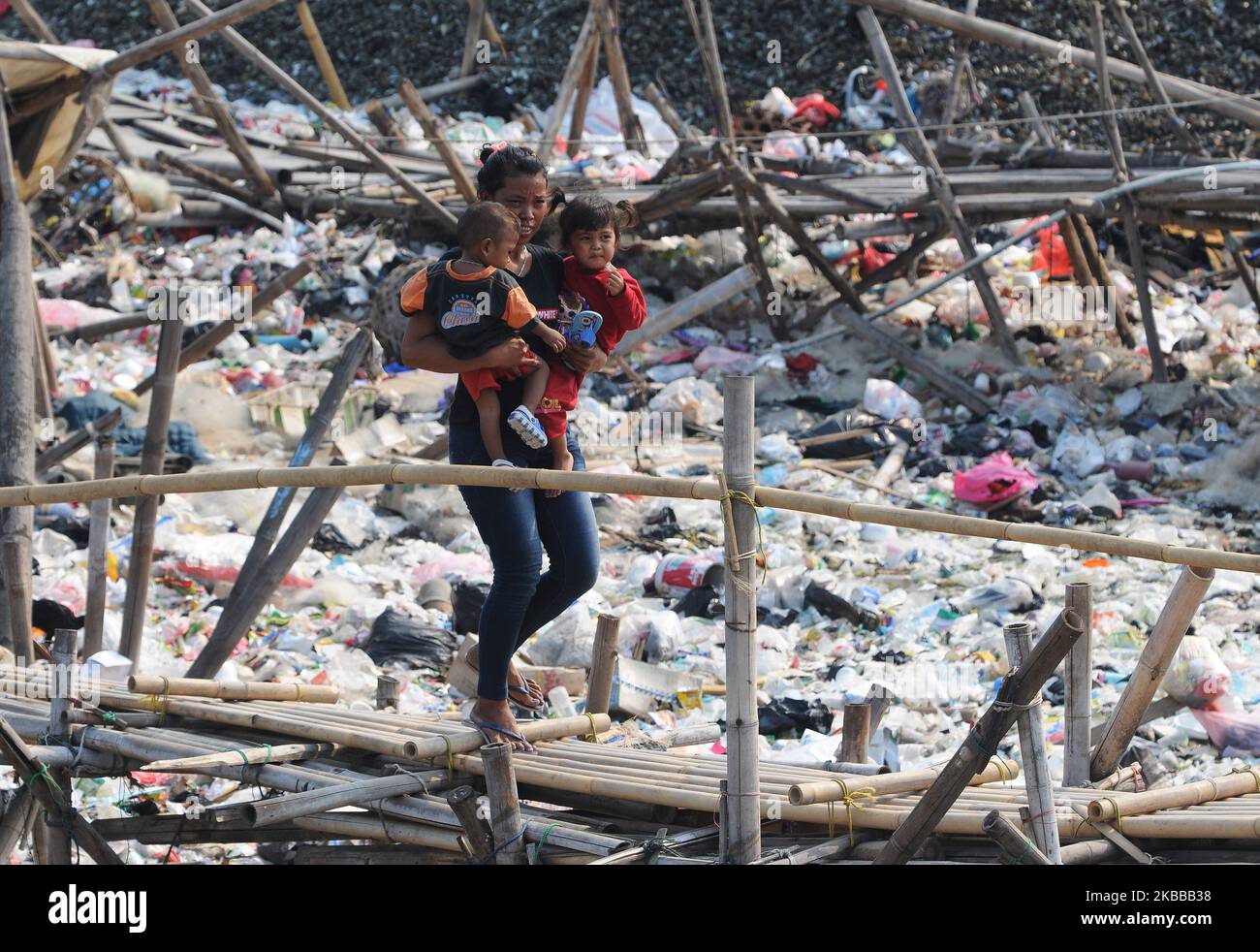 Mother and child cross a bamboo bridge in a slum on the coast ...