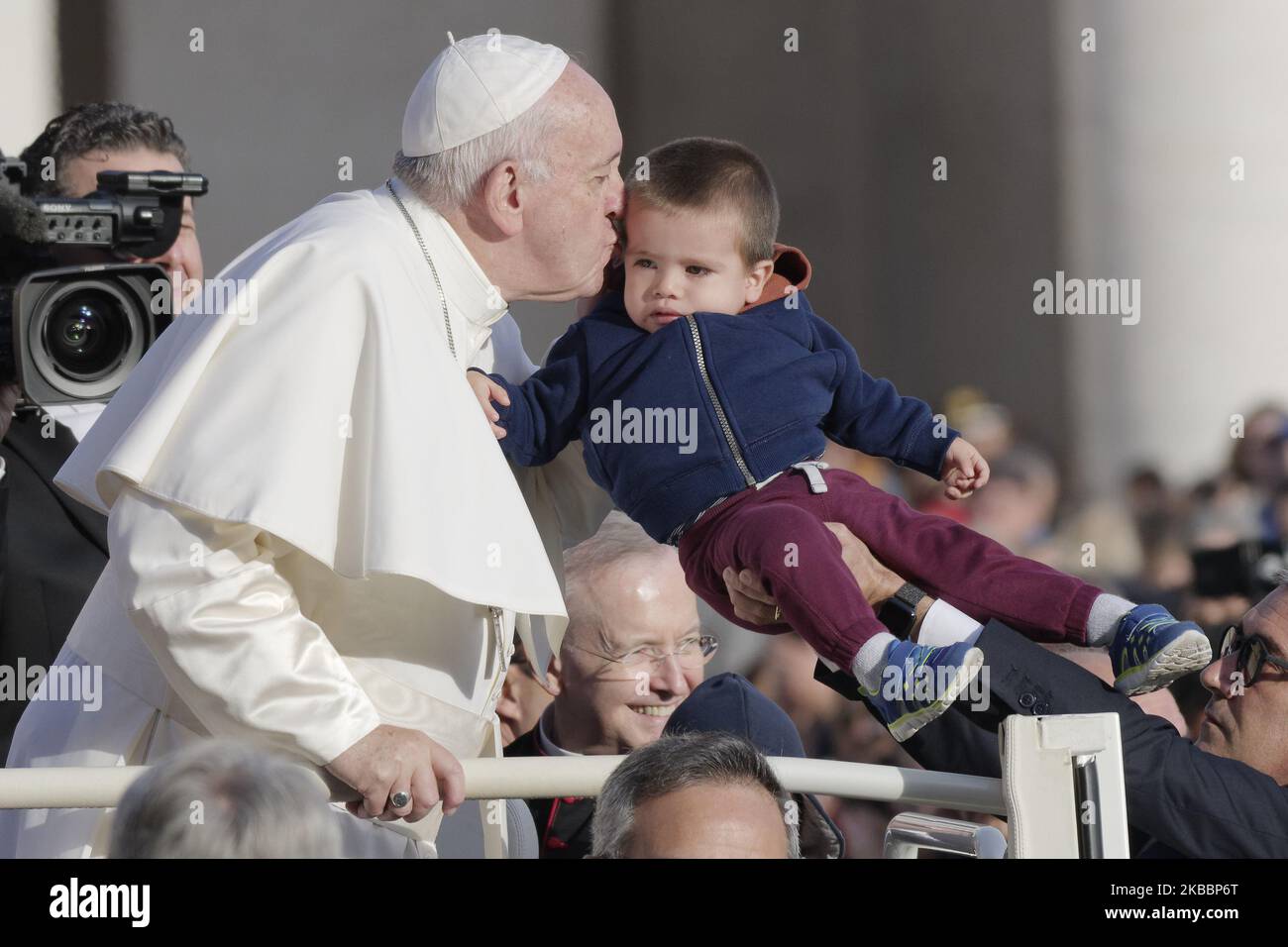 Pope Francis kisses a baby as he arrives for his weekly general ...