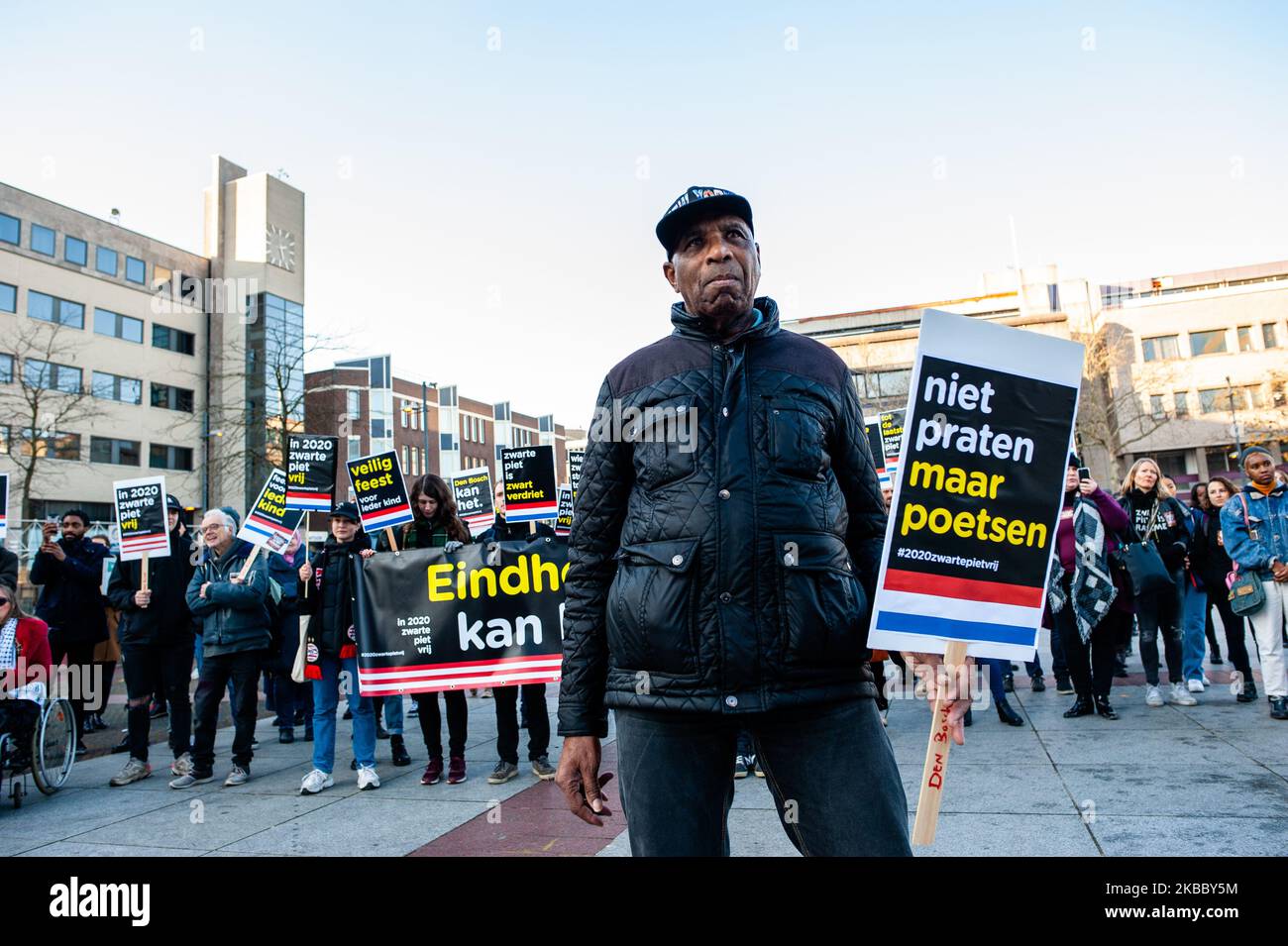 A Black man is holding a placard in front of the banners, during the ...