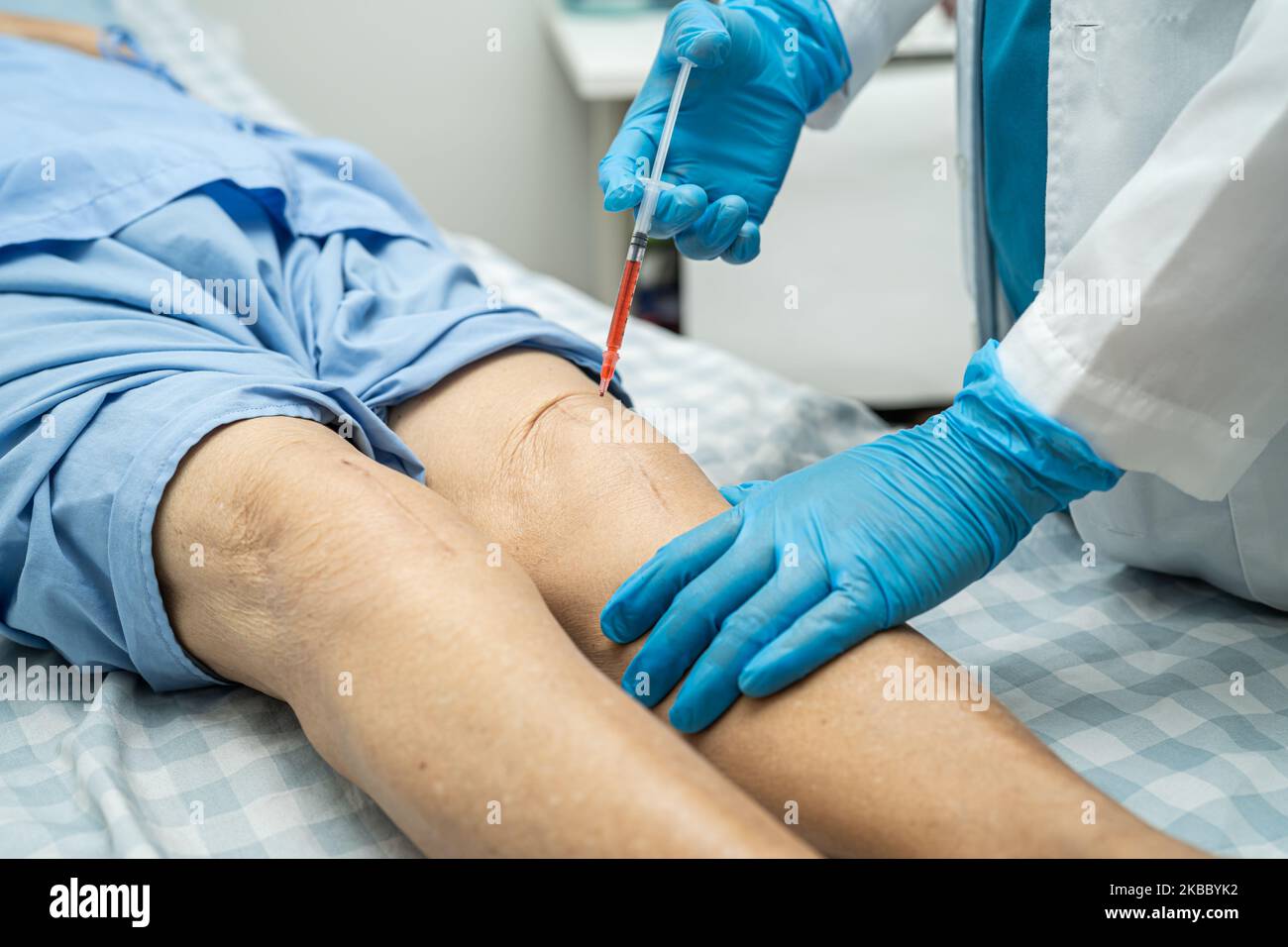 Asian doctor inject Hyaluronic acid platelet rich plasma into the knee of senior woman to walk ...