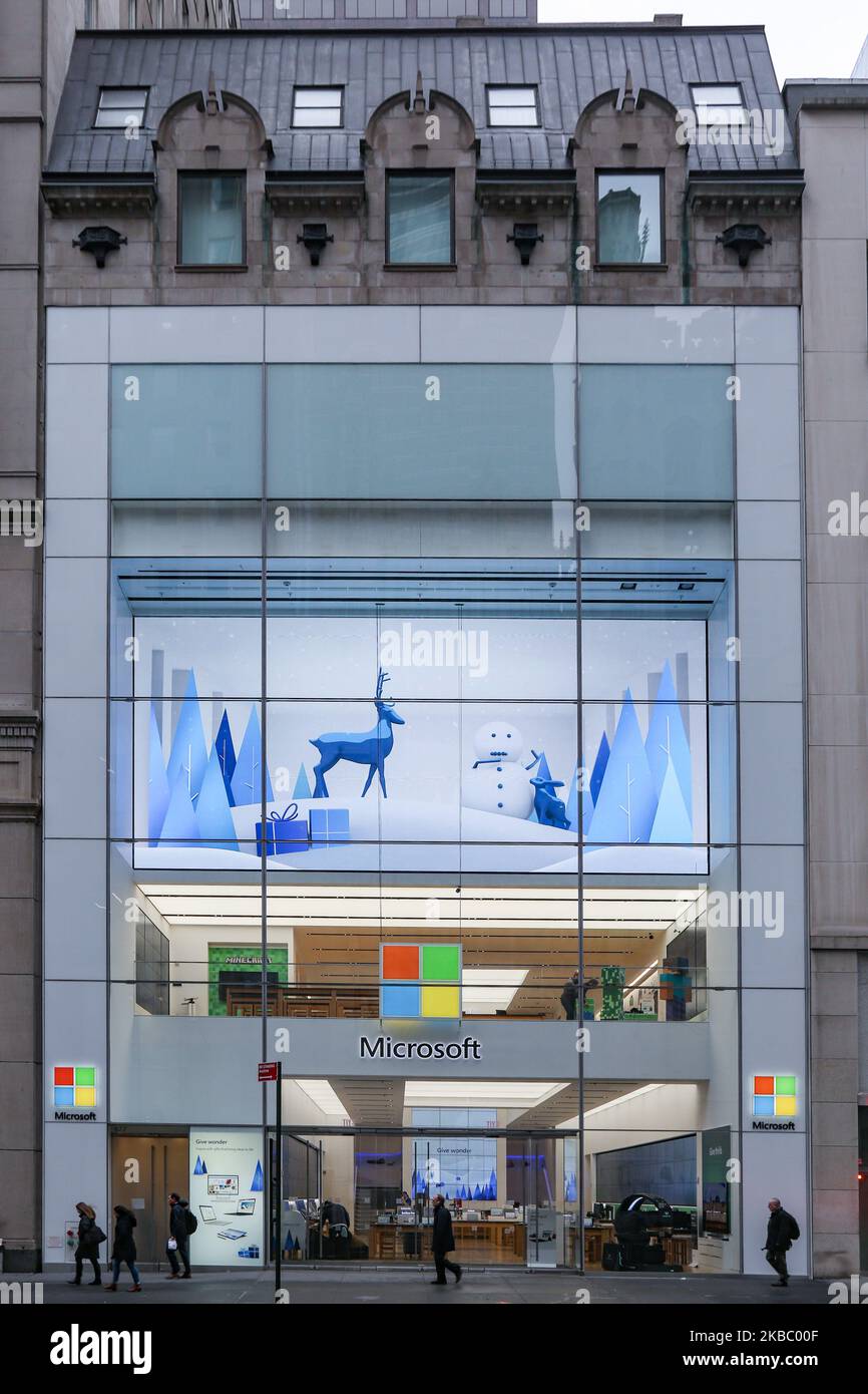 People walk past a Microsoft store entrance with the company's logo on ...