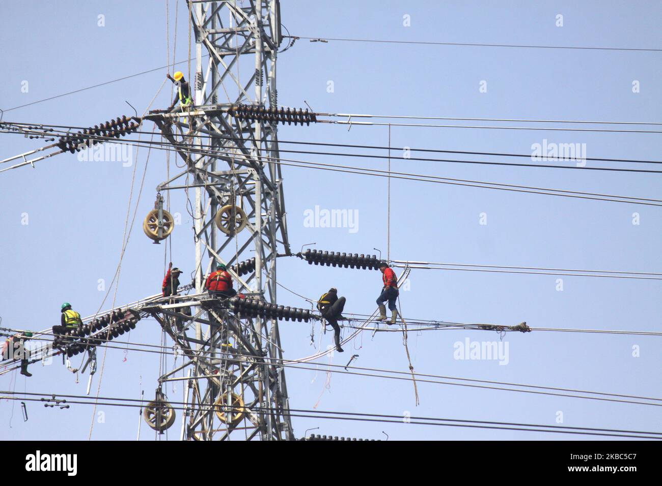 Workers assemble electricity installations on high voltage towers for ...
