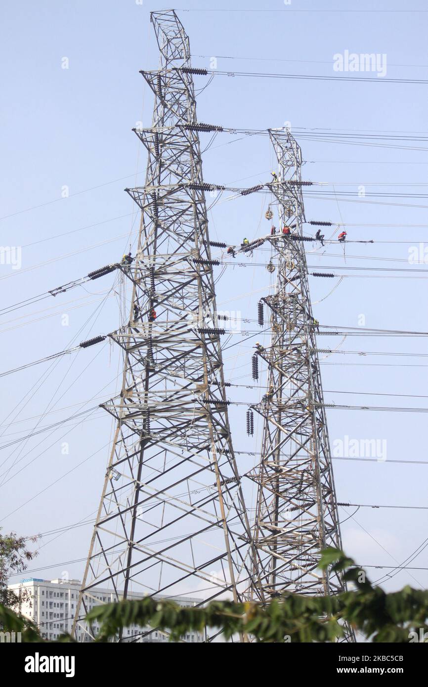 Workers assemble electricity installations on high voltage towers for ...