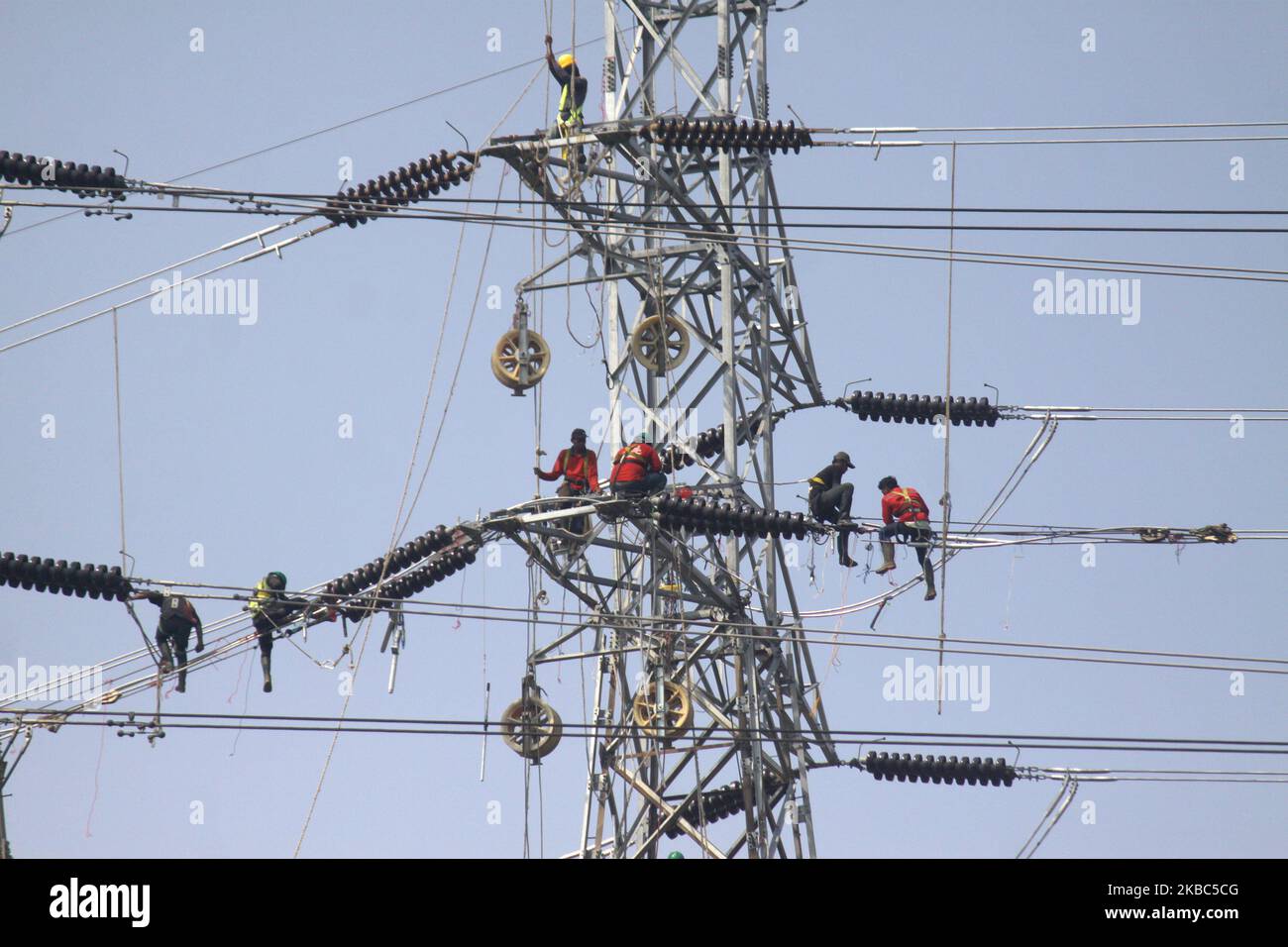 Workers assemble electricity installations on high voltage towers for ...