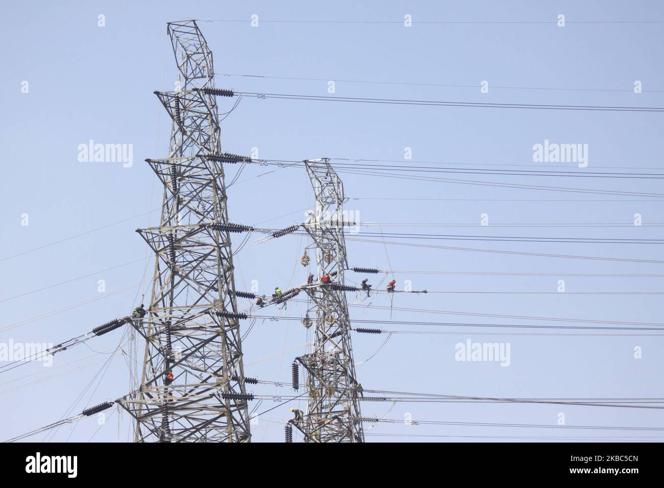 Workers assemble electricity installations on high voltage towers for ...