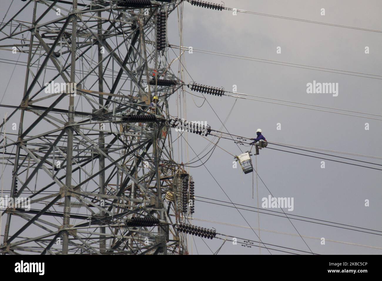 Workers assemble electricity installations on high voltage towers for ...