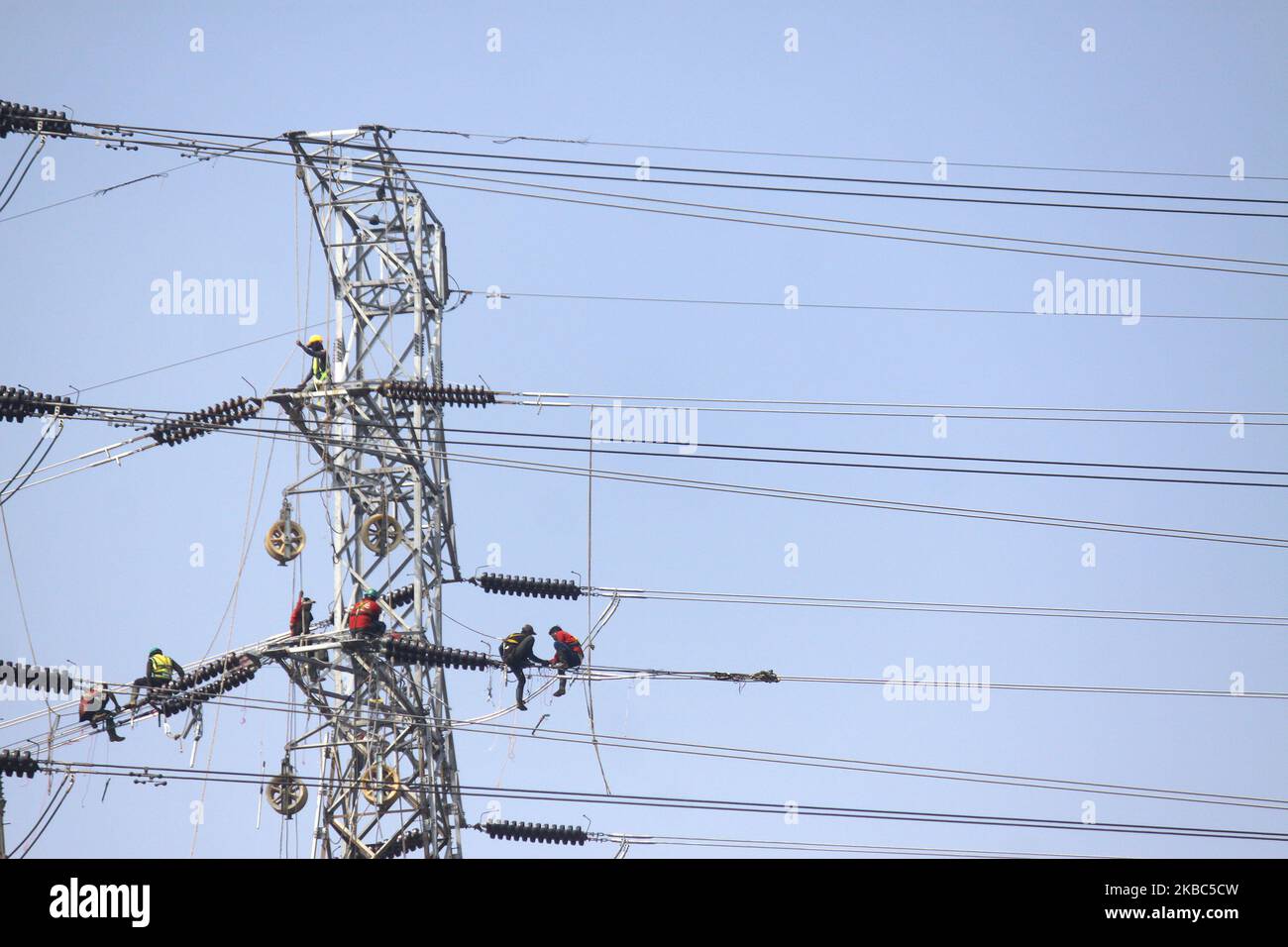 Workers assemble electricity installations on high voltage towers for ...