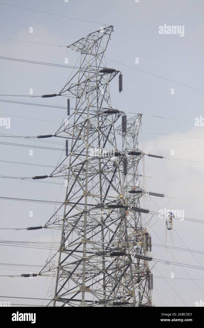 Workers assemble electricity installations on high voltage towers for ...
