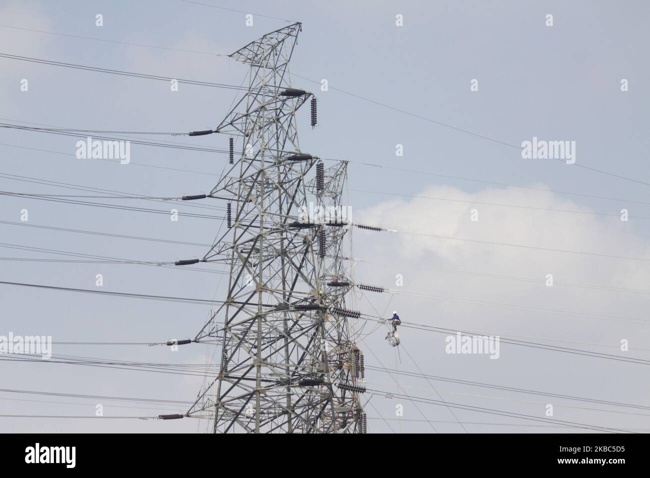 Workers assemble electricity installations on high voltage towers for ...