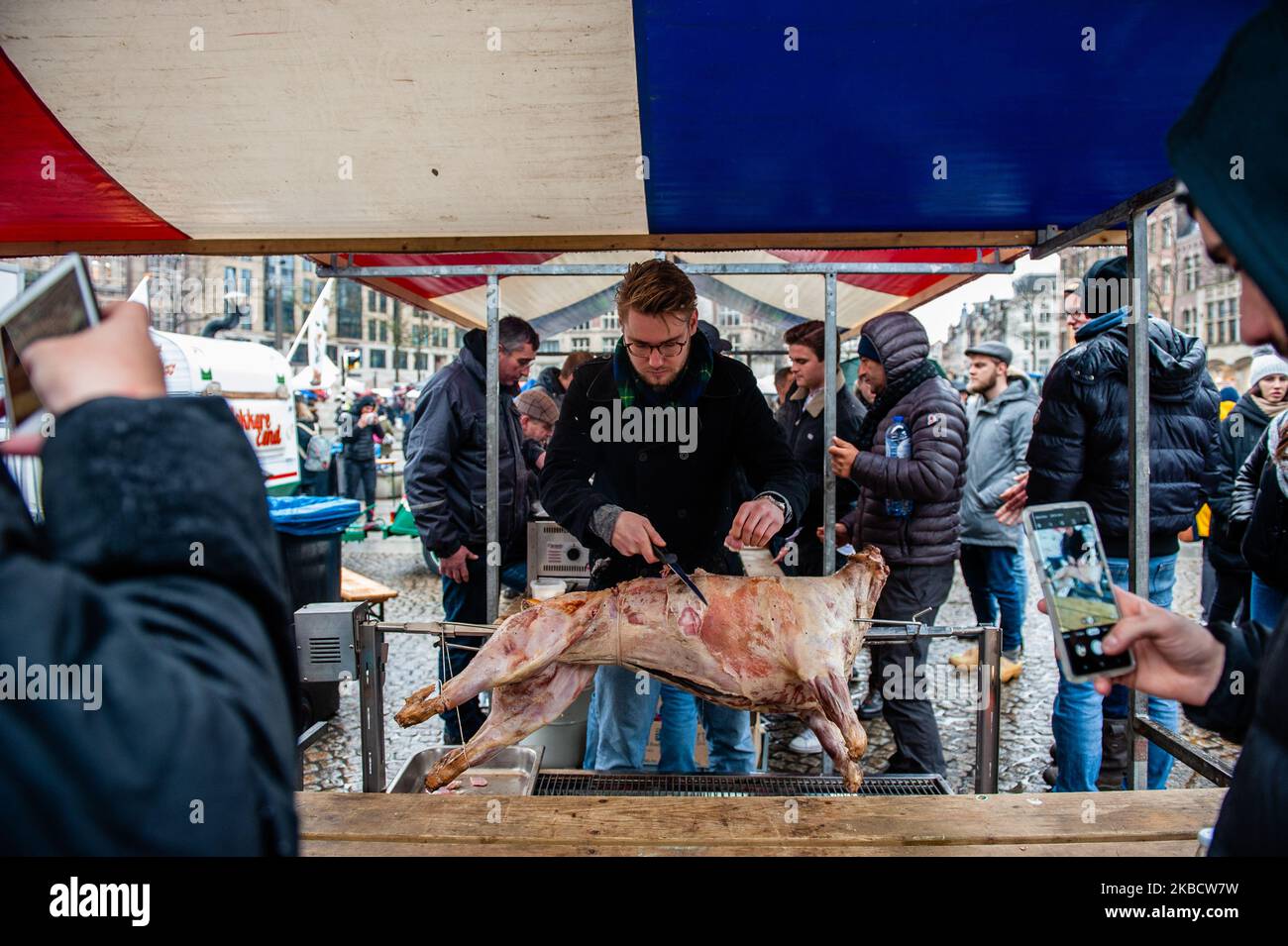 A farmer is cutting a roast pig in front of the people, during the ...