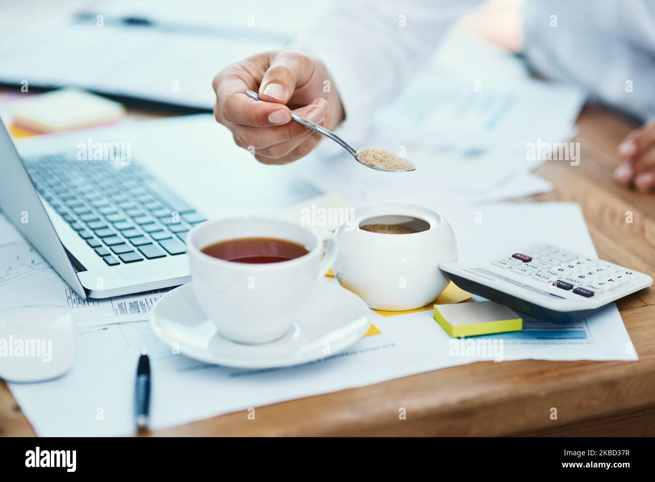 Adding some sweetener to his drink. an unrecognizable businessman ...