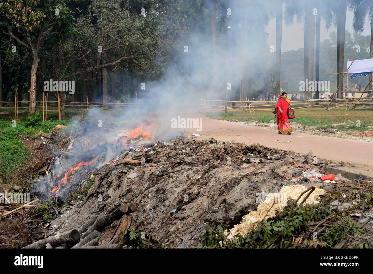 People walking as the garbage are burning beside a road in a park in ...