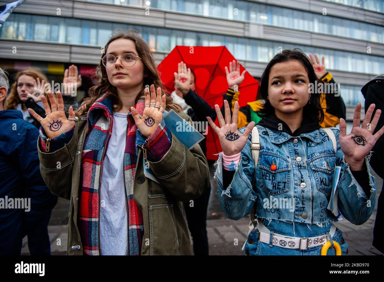 Several climate activists are showing their hands with eyes painted on ...