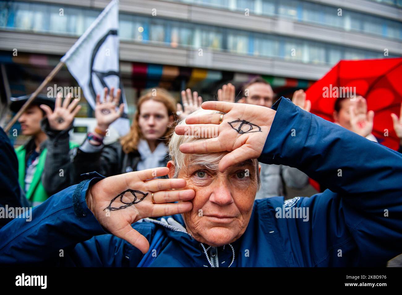 A climate activist is showing her hands with eyes painted on them ...