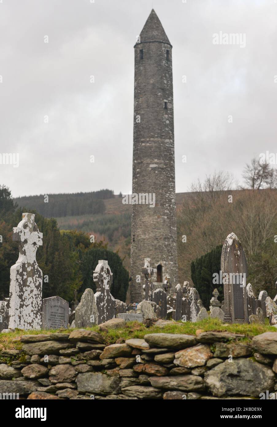 A view of an Irish round tower, tombstones and Celtic crosses inside an ...