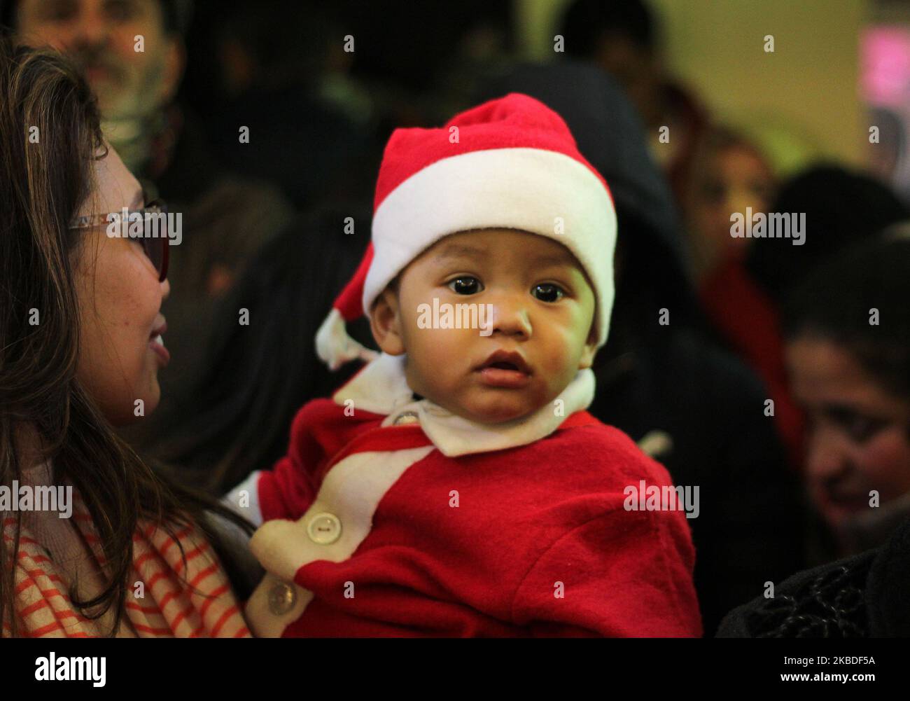 A kid dressed as Santa Claus attends prayer with his mother at the holy ...