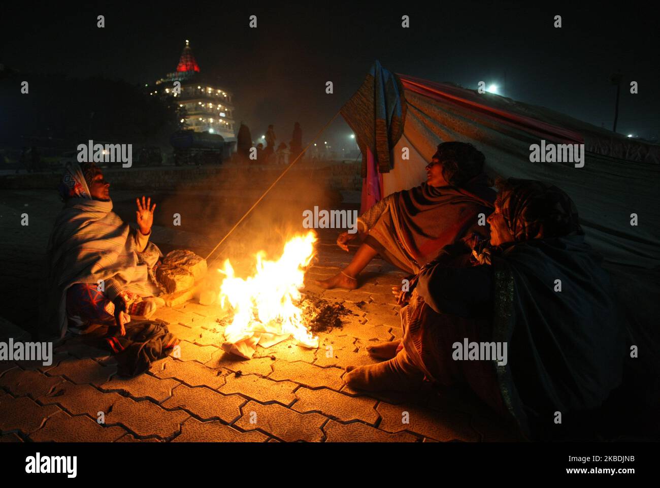 people sit around bonfire to warm themselves , during a cold evening in ...