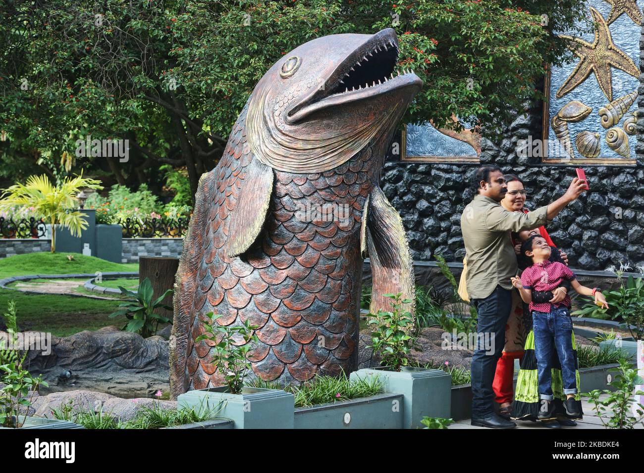 People take a selfie by a large sculpture of a giant prehistoric fish ...