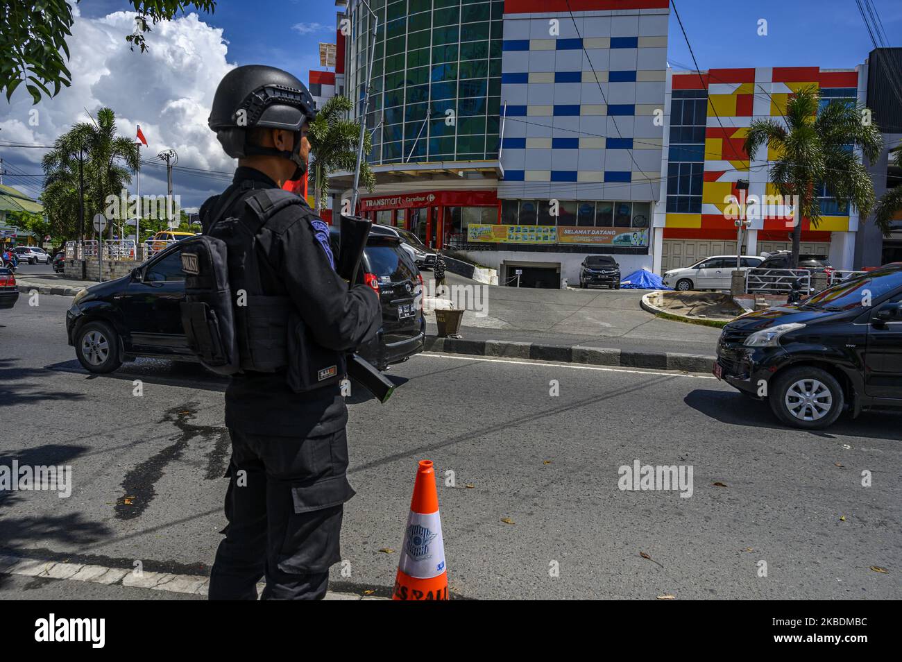 An armed police officer stands guard on one of the roads in Palu ...