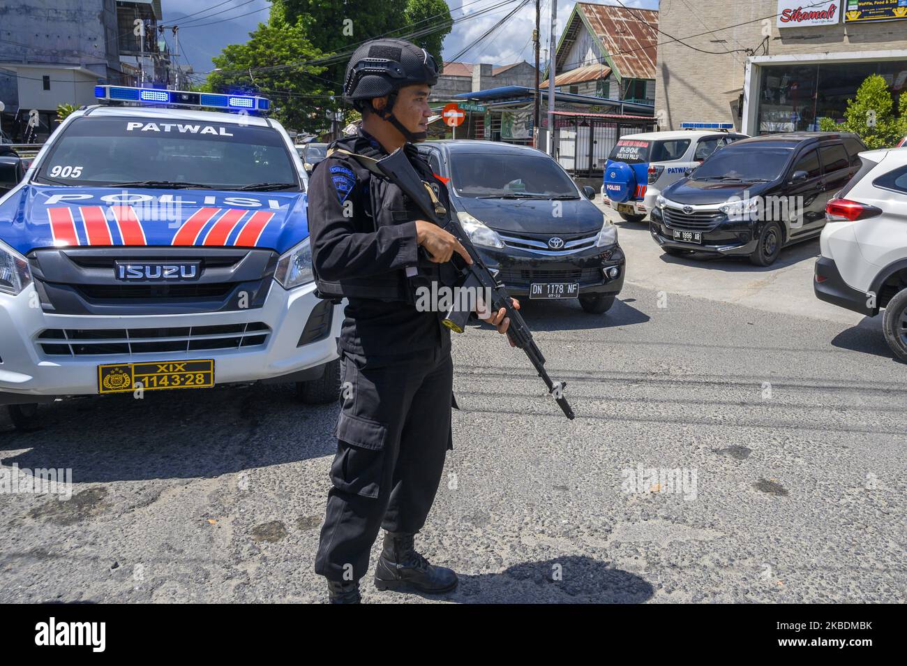 An armed police officer stands guard on one of the roads in Palu ...