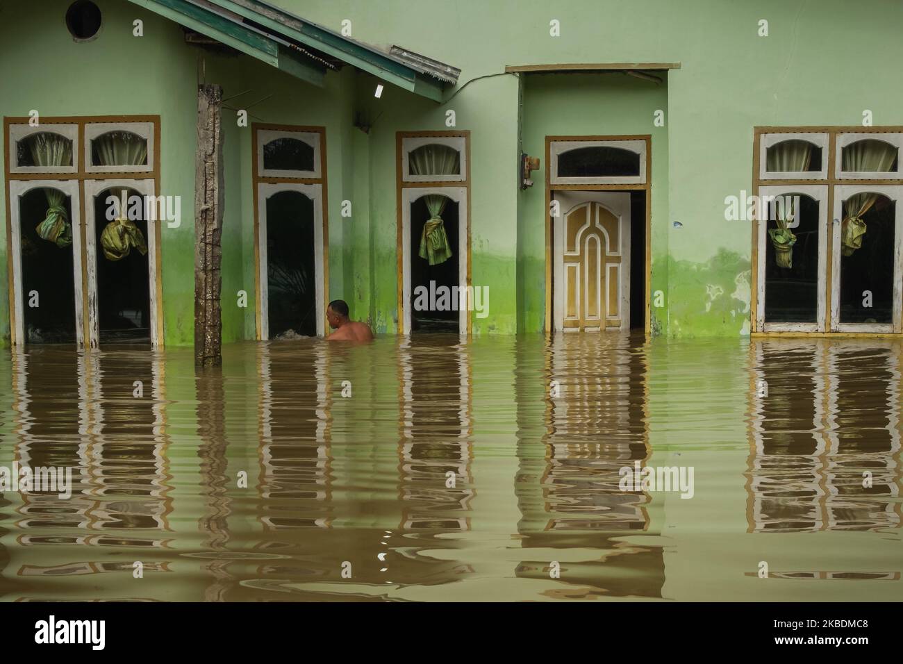 A man walks through flood water at Buluh Cina village on December 31 ...
