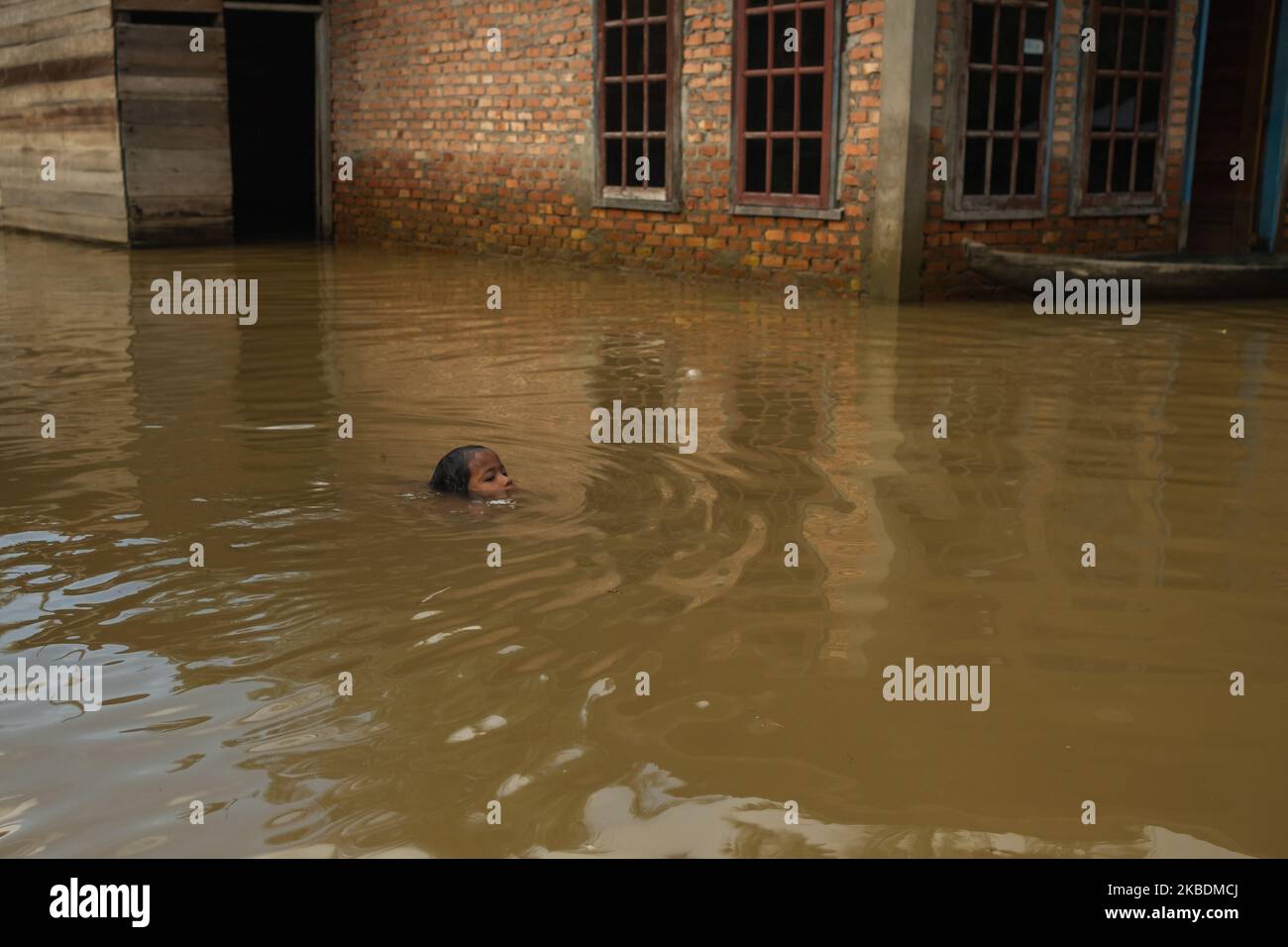 A Children swims through flood water at Buluh Cina village on December ...