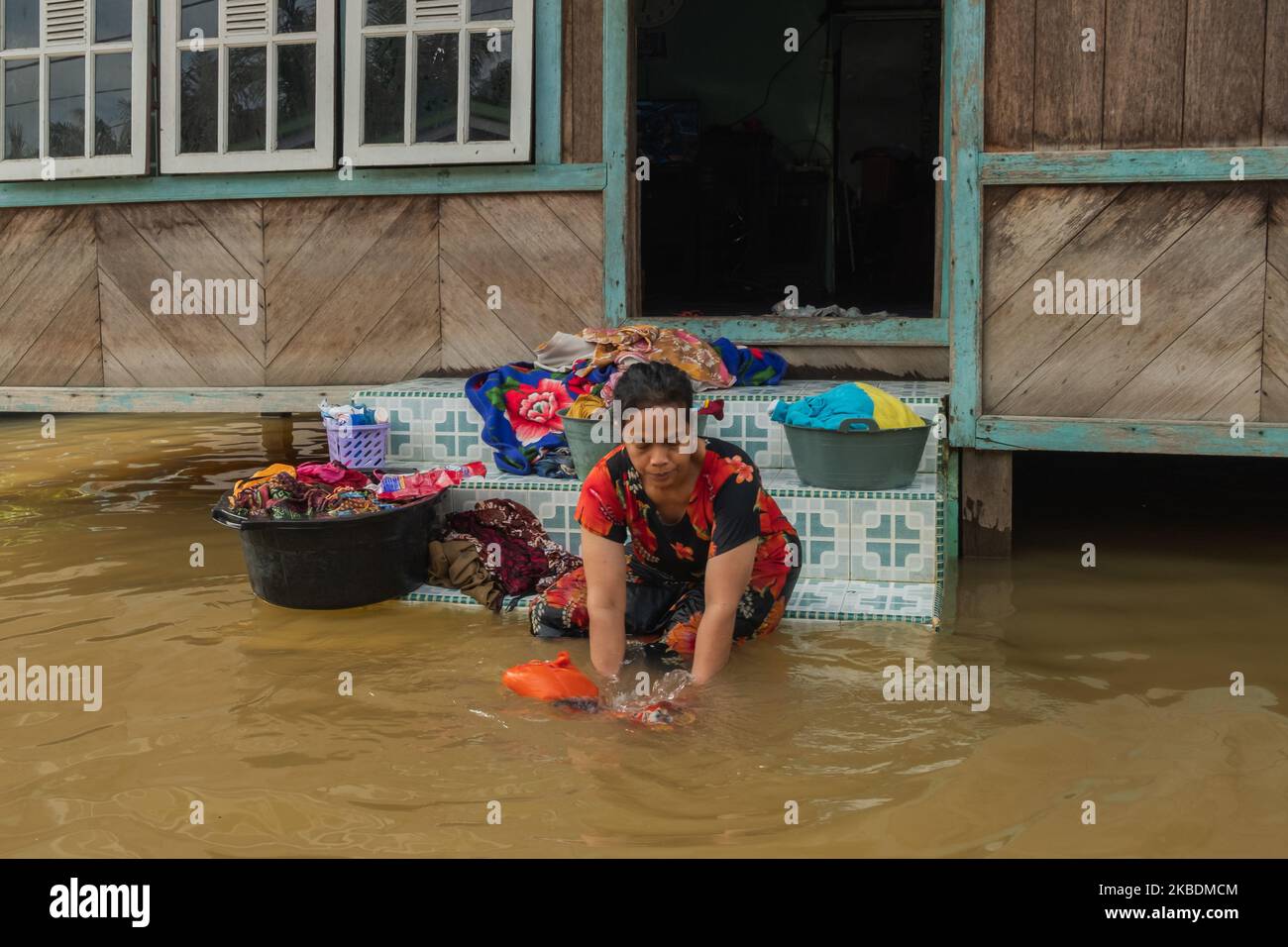 A woman washing clothes in flood water at Buluh Cina village on ...
