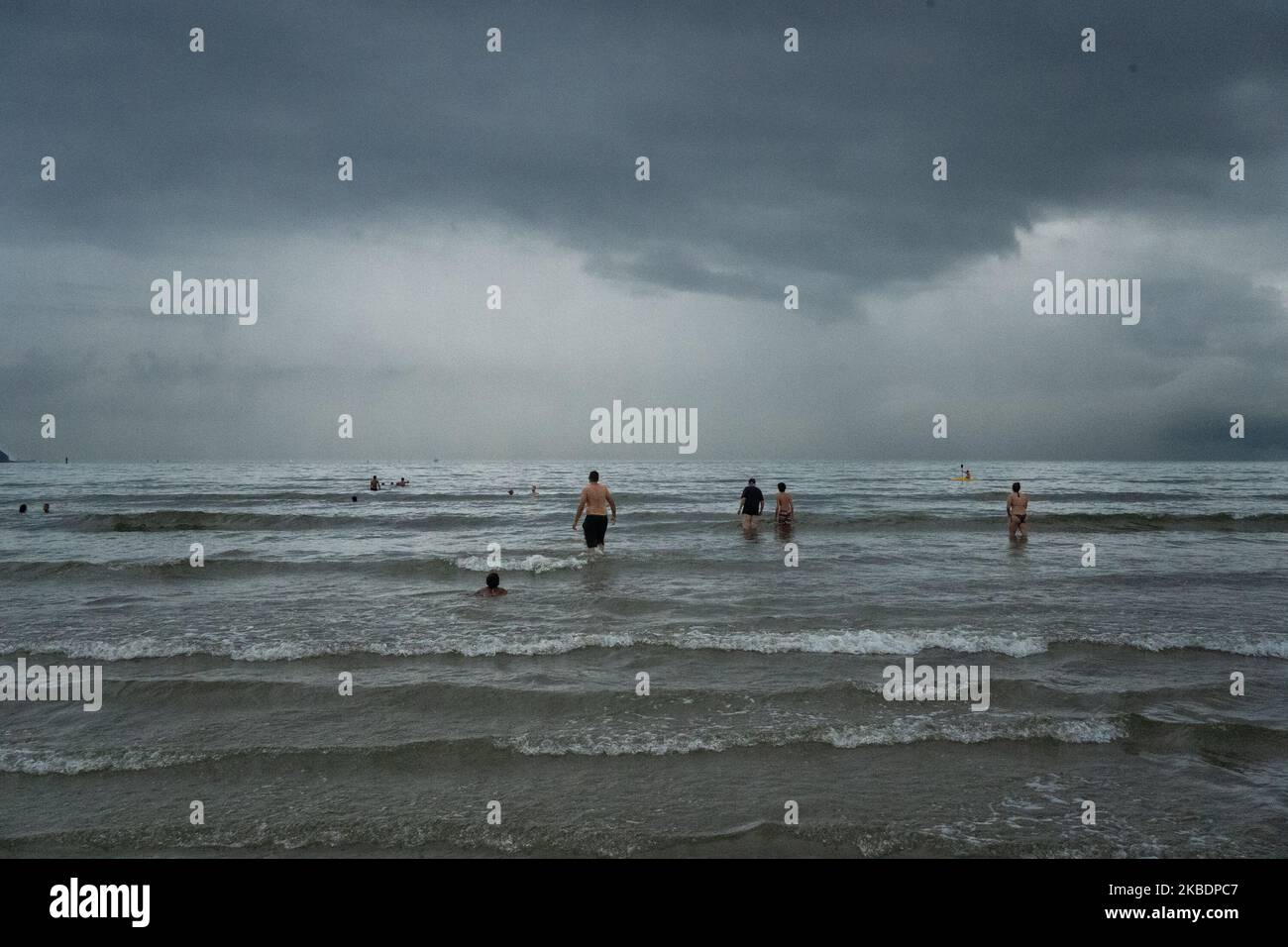 People in the sea at Boqueirão beach, during summer rain in Santos ...
