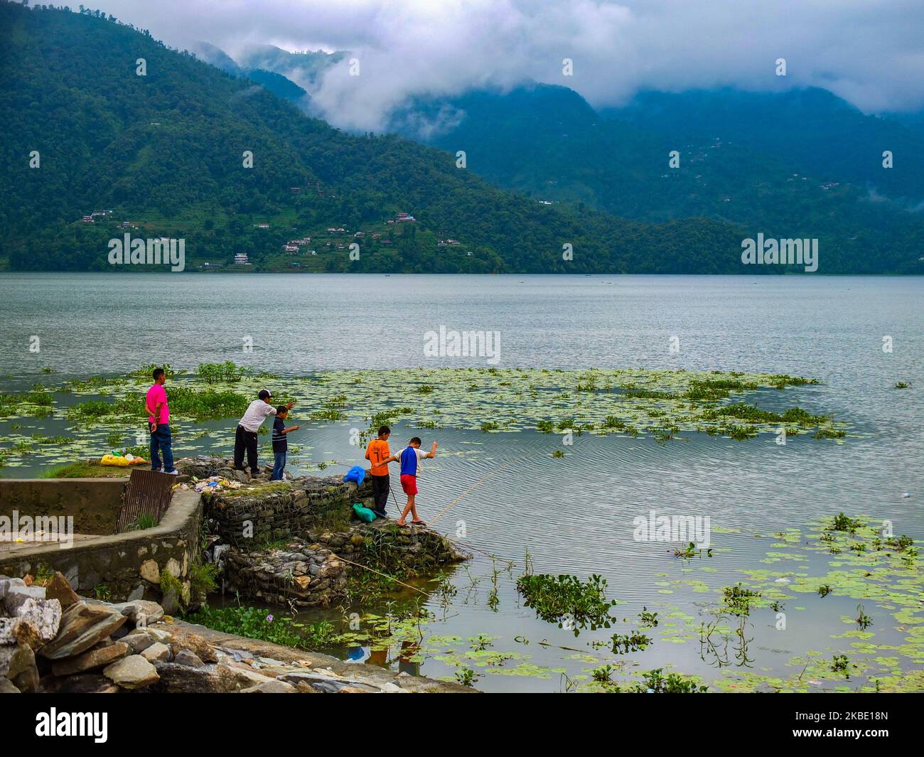 A group of men fish along the shores of Phewa Lake, in Pohkara, Nepal ...