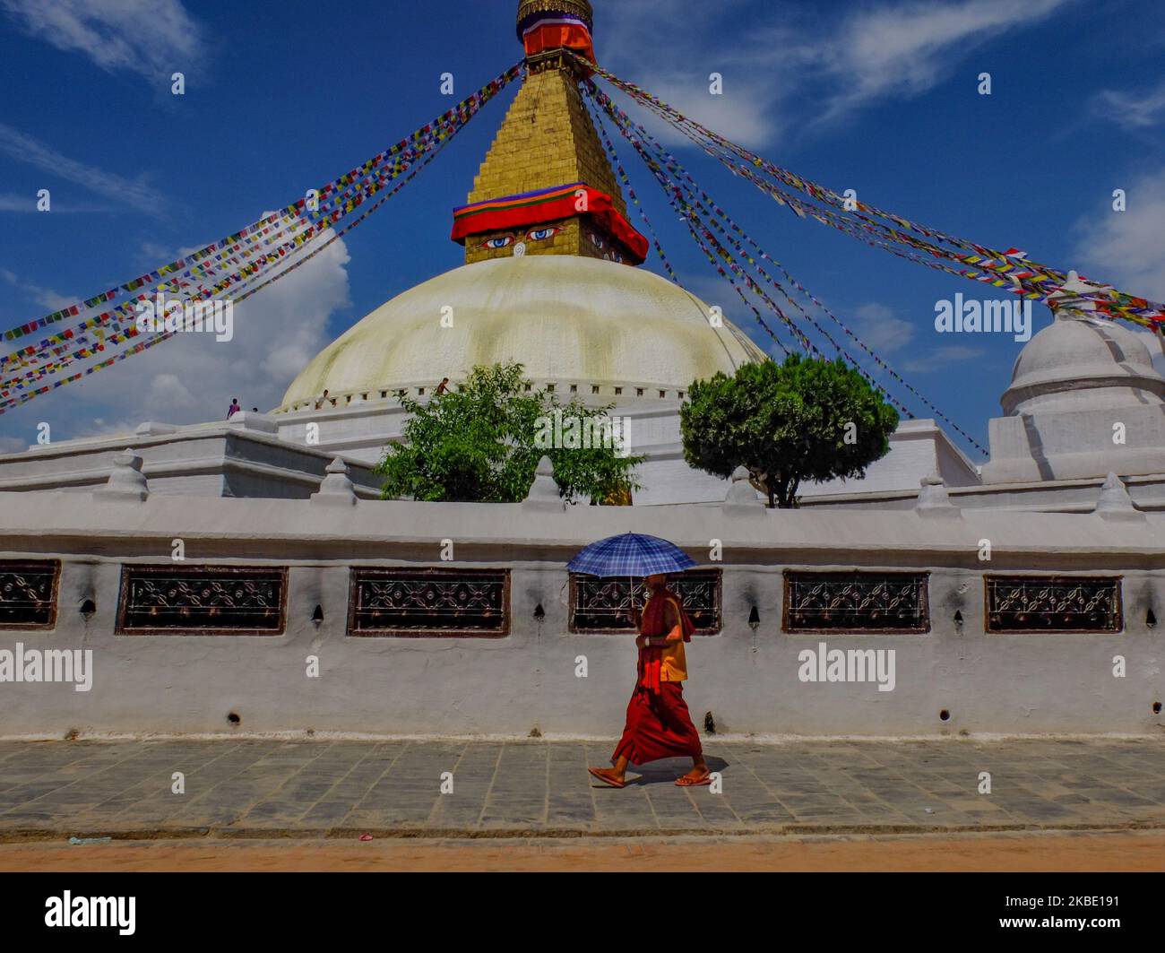 A Buddhist monk walks along the Boudhanath Stupa in Kathmandu, Nepal ...