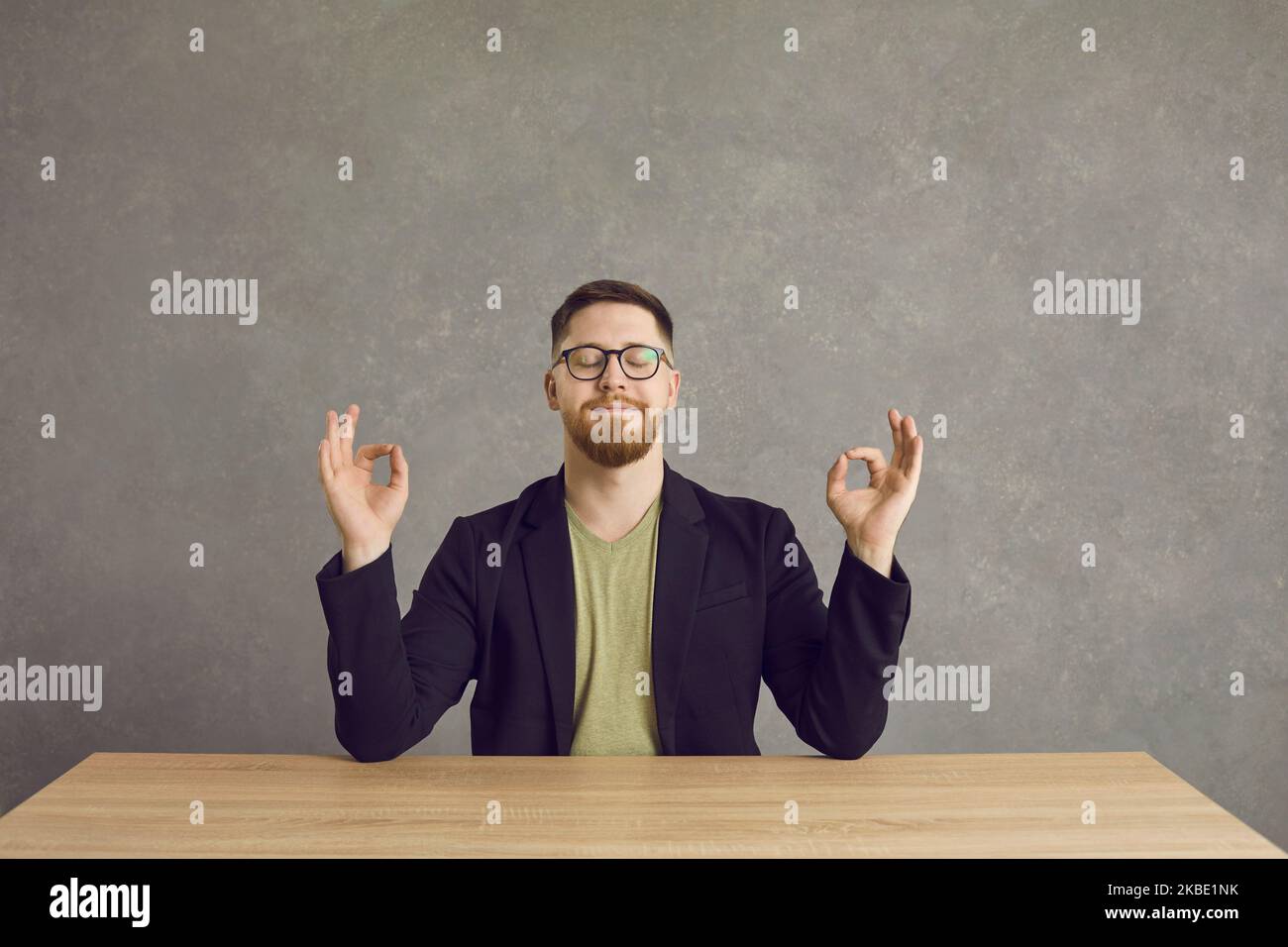 Calm man sitting at working desk, meditating, doing yoga exercise and ...