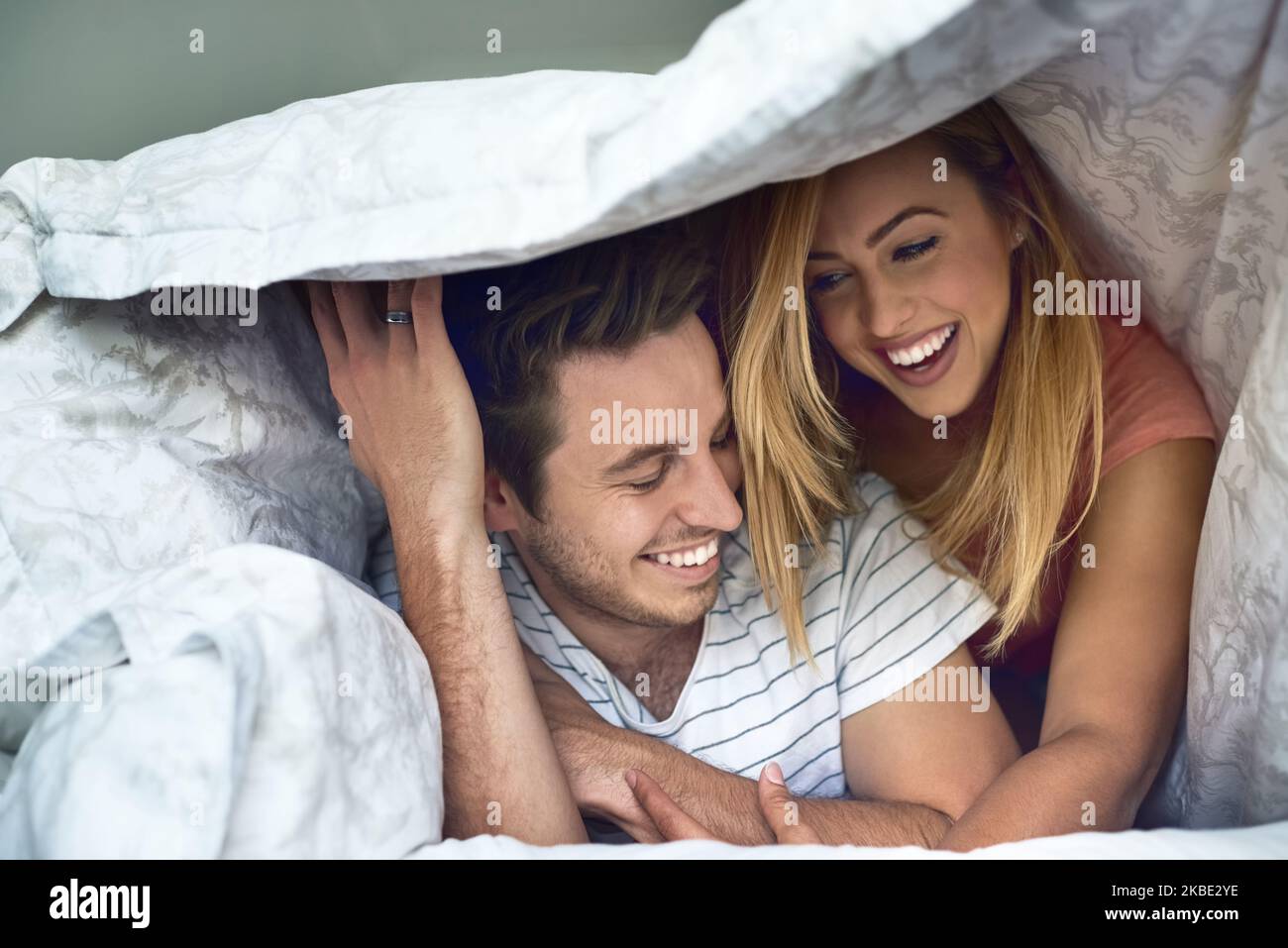 Delightfully in love. a happy young couple having fun under a duvet in ...