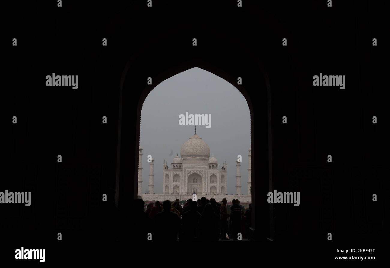 People stand at the entrance gate of Taj Mahal under heavy smog ...
