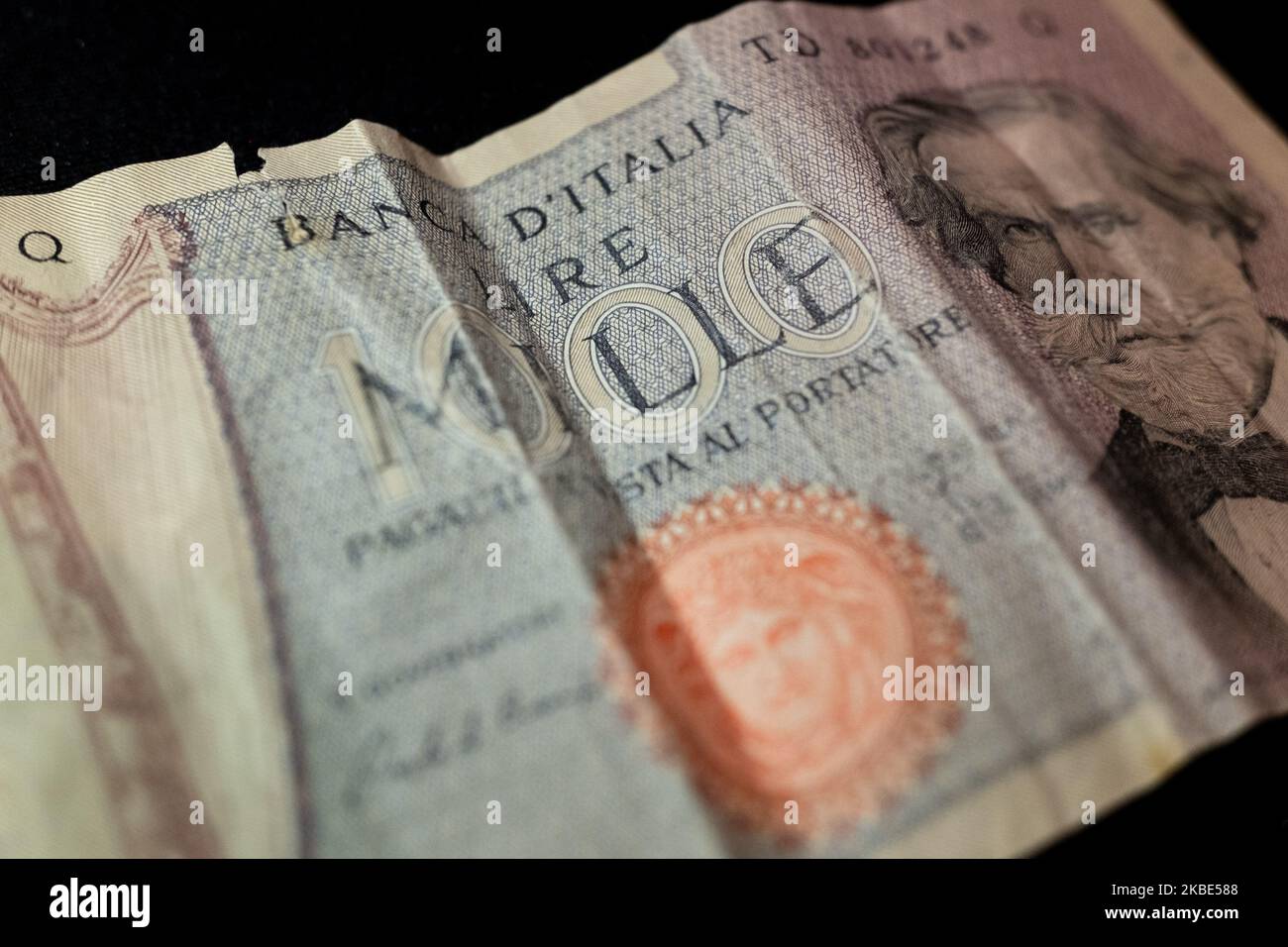 Two old Italian Lira currency banknotes are displayed on a black ...