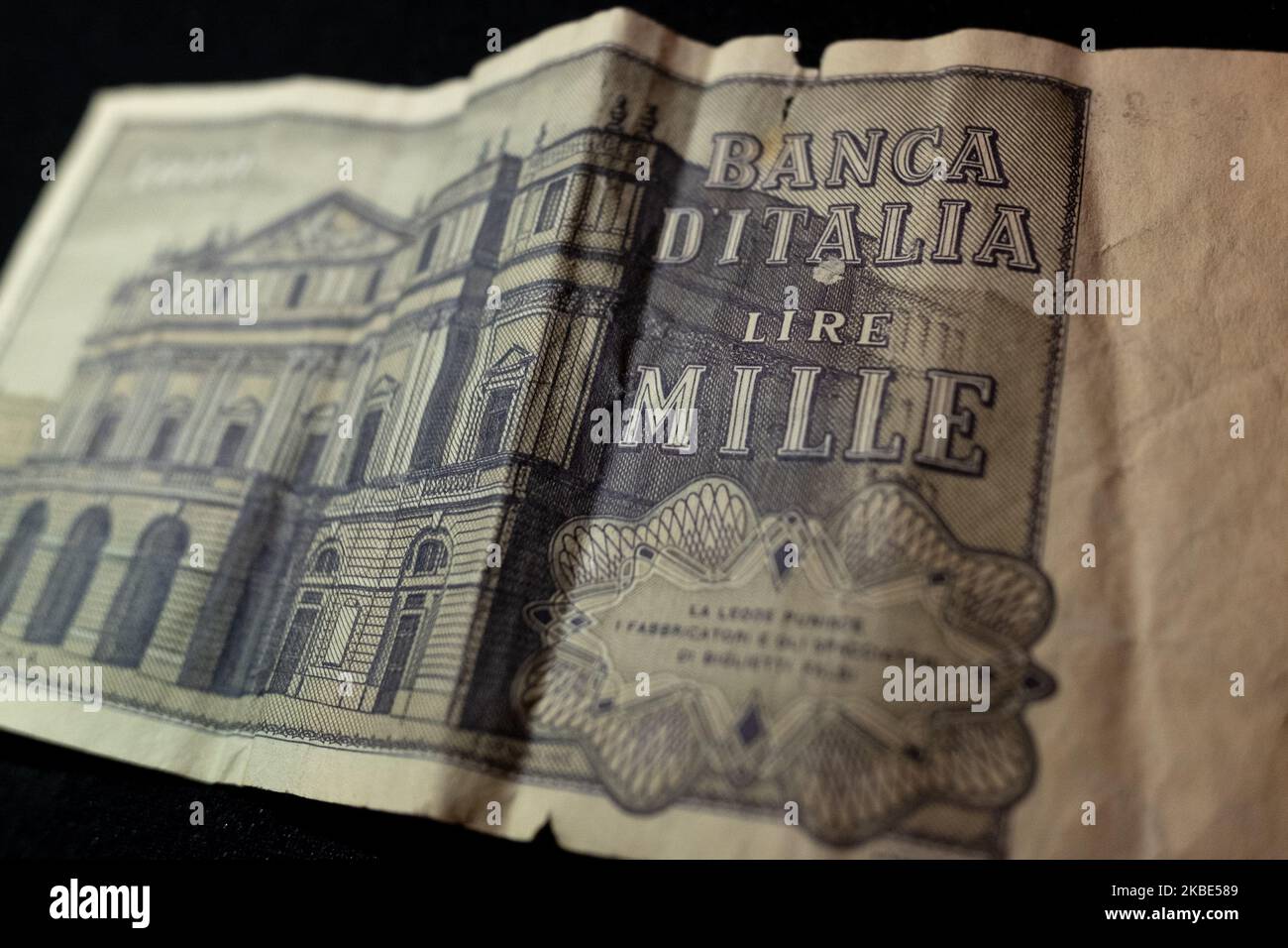 Two old Italian Lira currency banknotes are displayed on a black ...