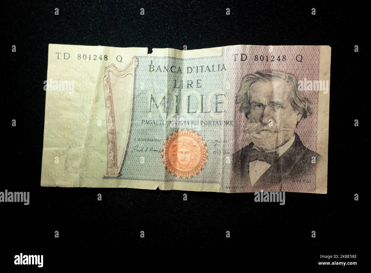 Two old Italian Lira currency banknotes are displayed on a black ...