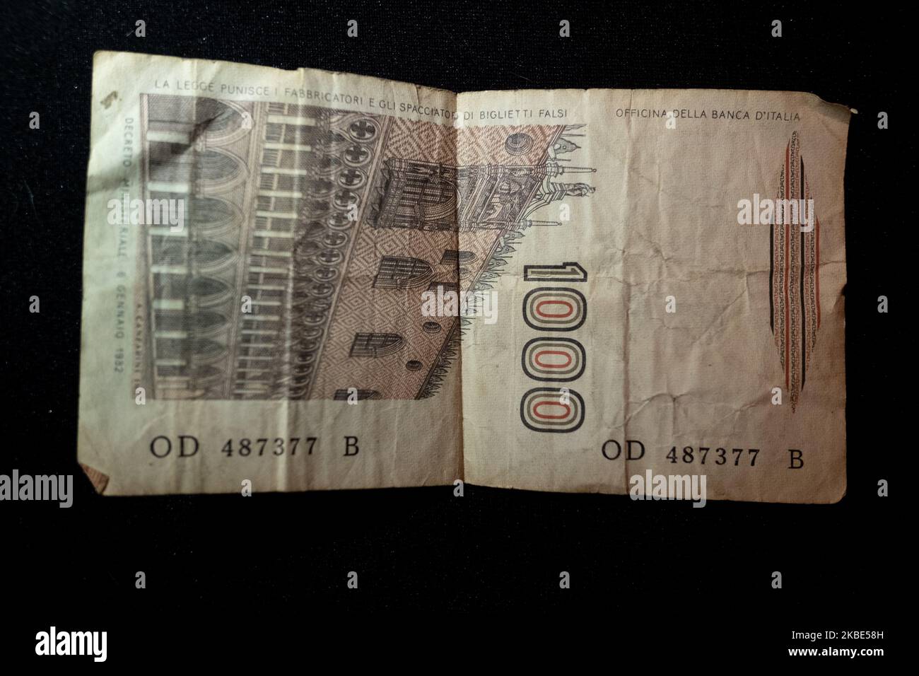Two old Italian Lira currency banknotes are displayed on a black ...