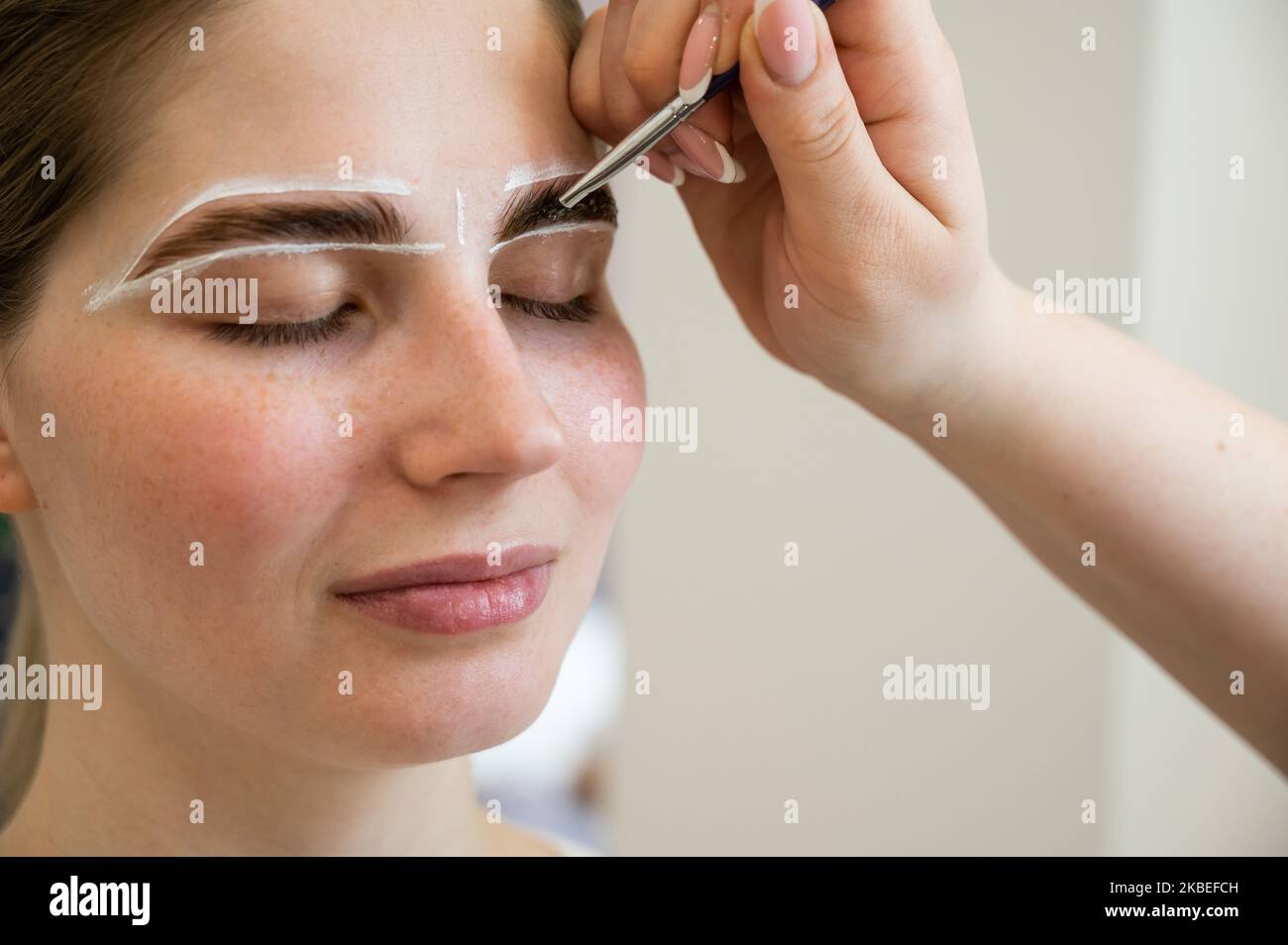 The master draws the shape of the eyebrows with white paint before ...