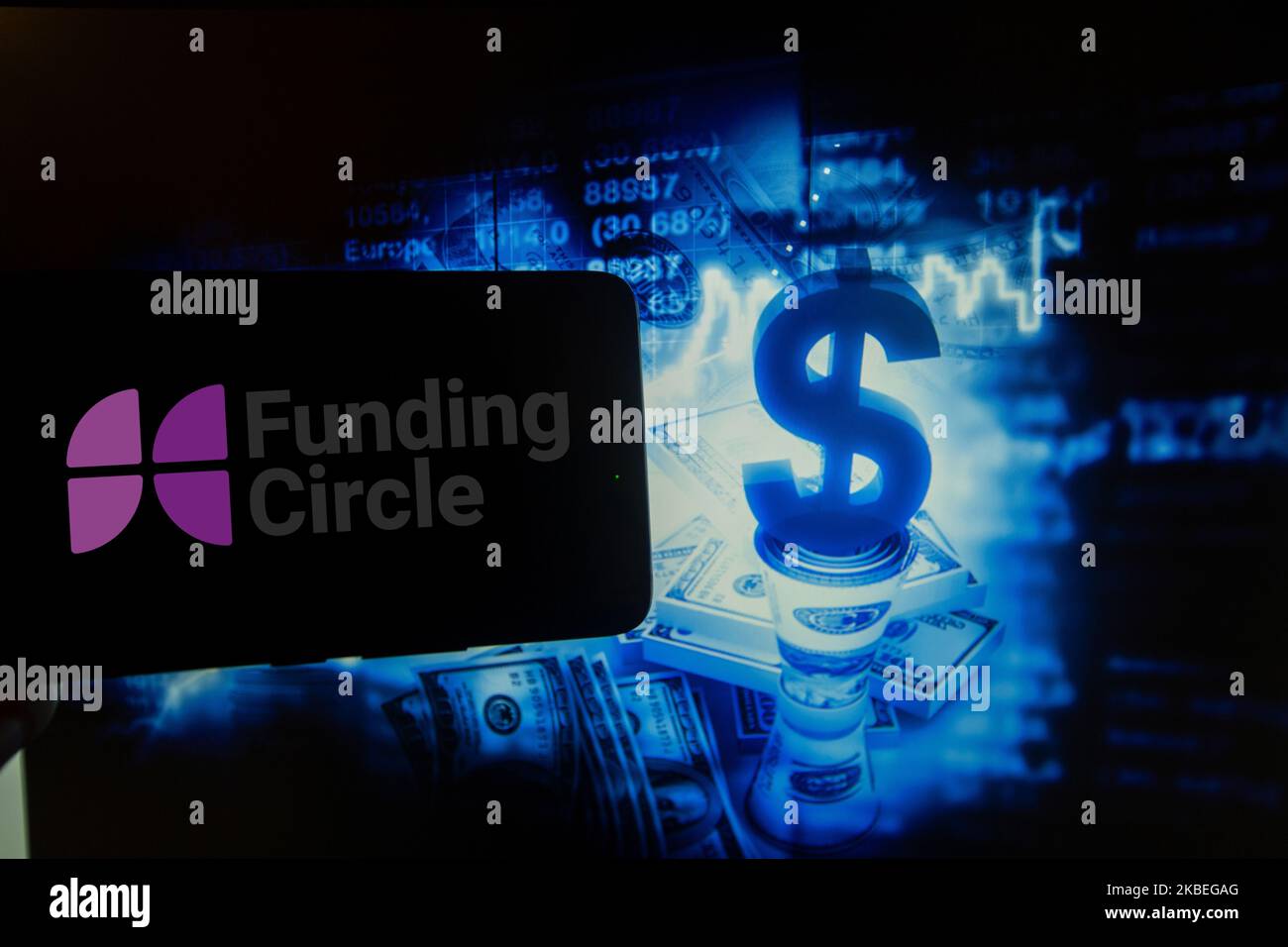 The logo of Funding Circle is seen on a screen of a smartphone next to an illustration of money ...