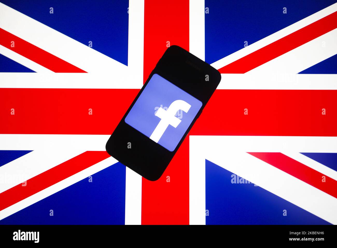 Facebook logo is displayed on a mobile phone screen photographed on UK ...