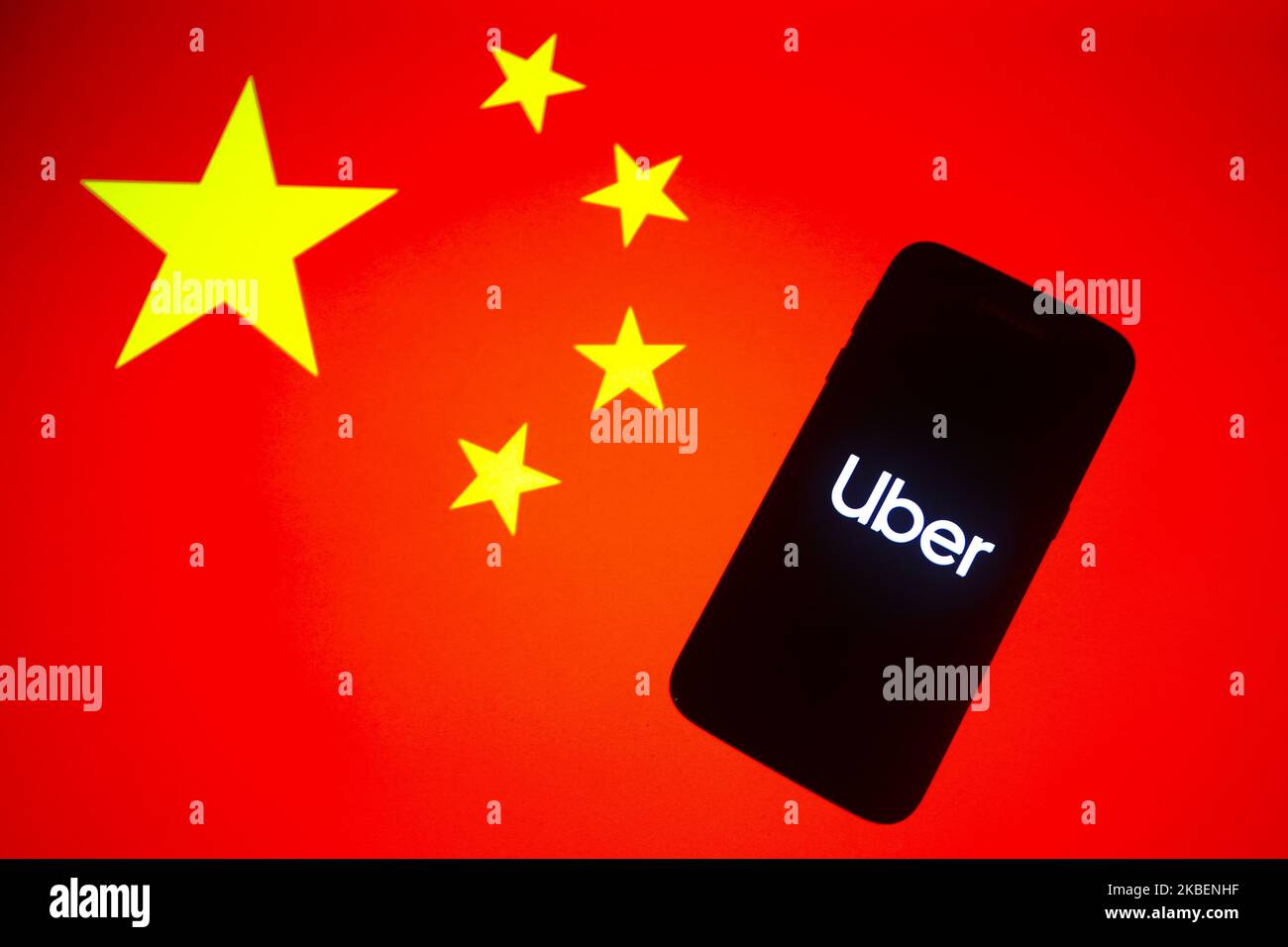 Uber logo is displayed on a mobile phone screen photographed on the ...