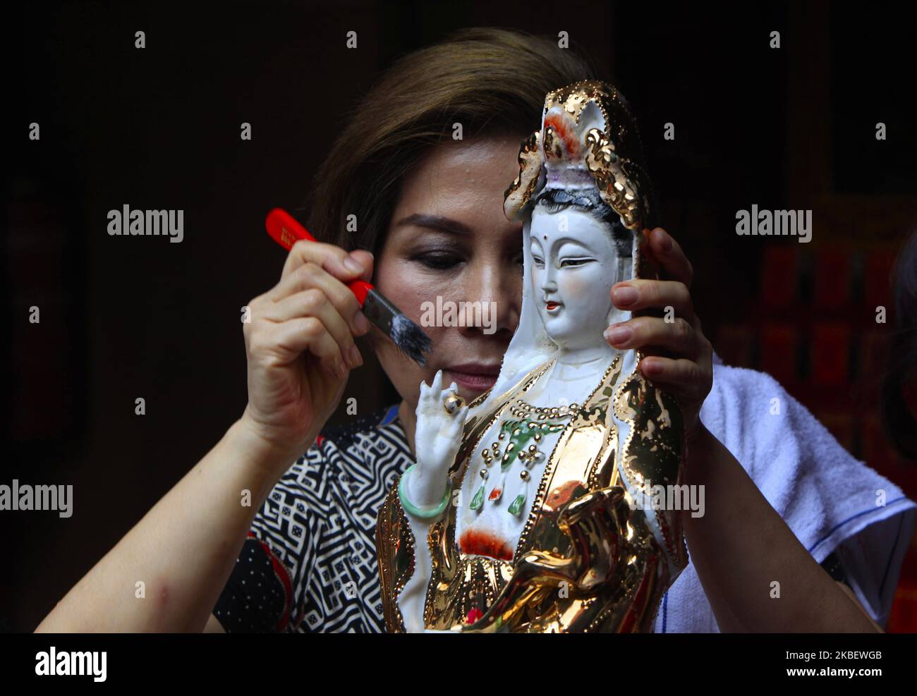 A woman cleans the goddess statue in Dhanagun Temple, Bogor, West Java ...