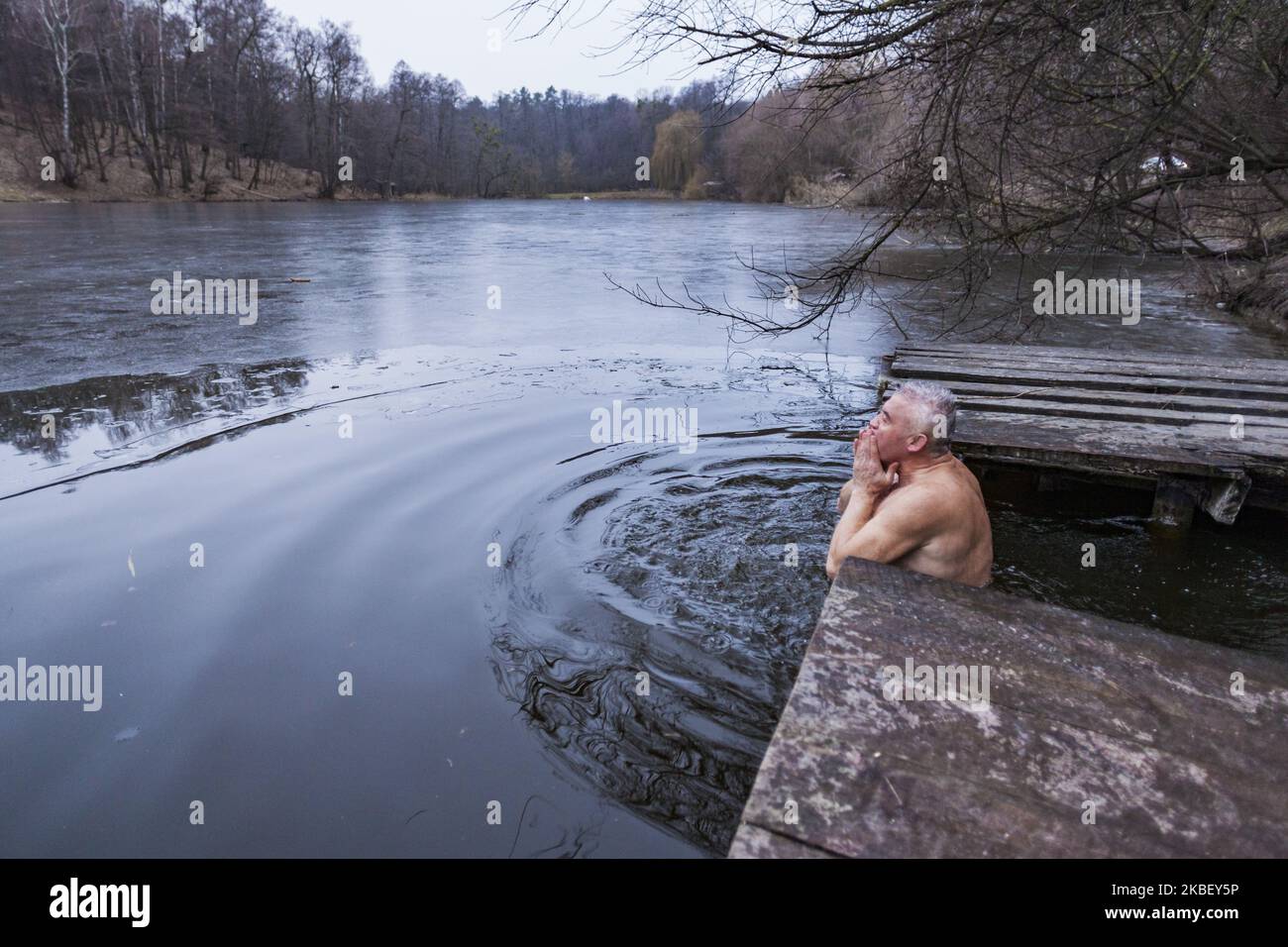 A man prays before taking a dip ice bath in a frozen lake to celebrate ...