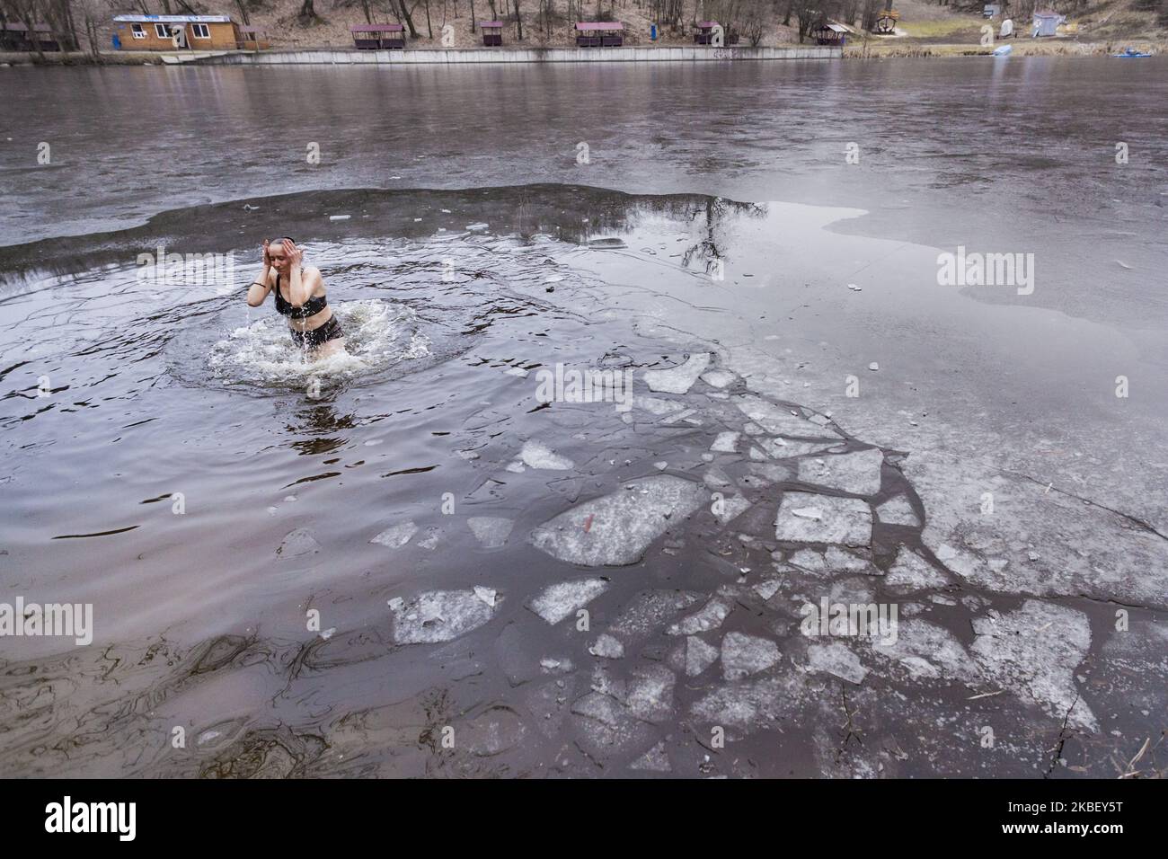 A woman takes a dip bath among ice of a frozen lake to celebrate the ...