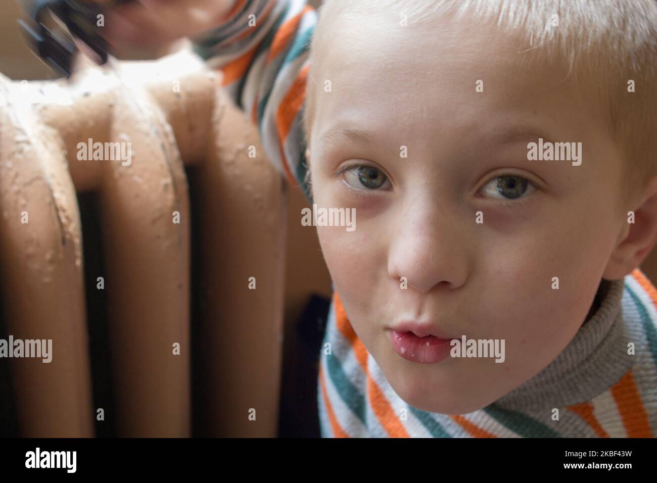 boy basking near old cast iron radiator in room Stock Photo - Alamy
