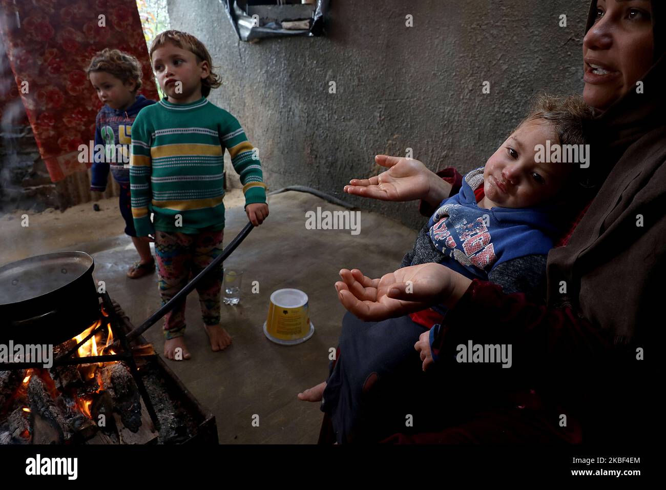 A Palestinian family warm themselves by a fire near their makeshift ...