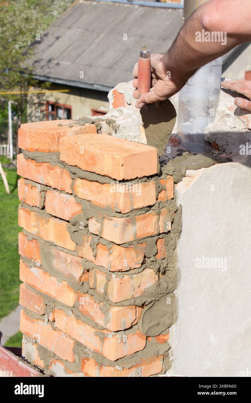 Builder mason building a chimney on the roof Stock Photo - Alamy